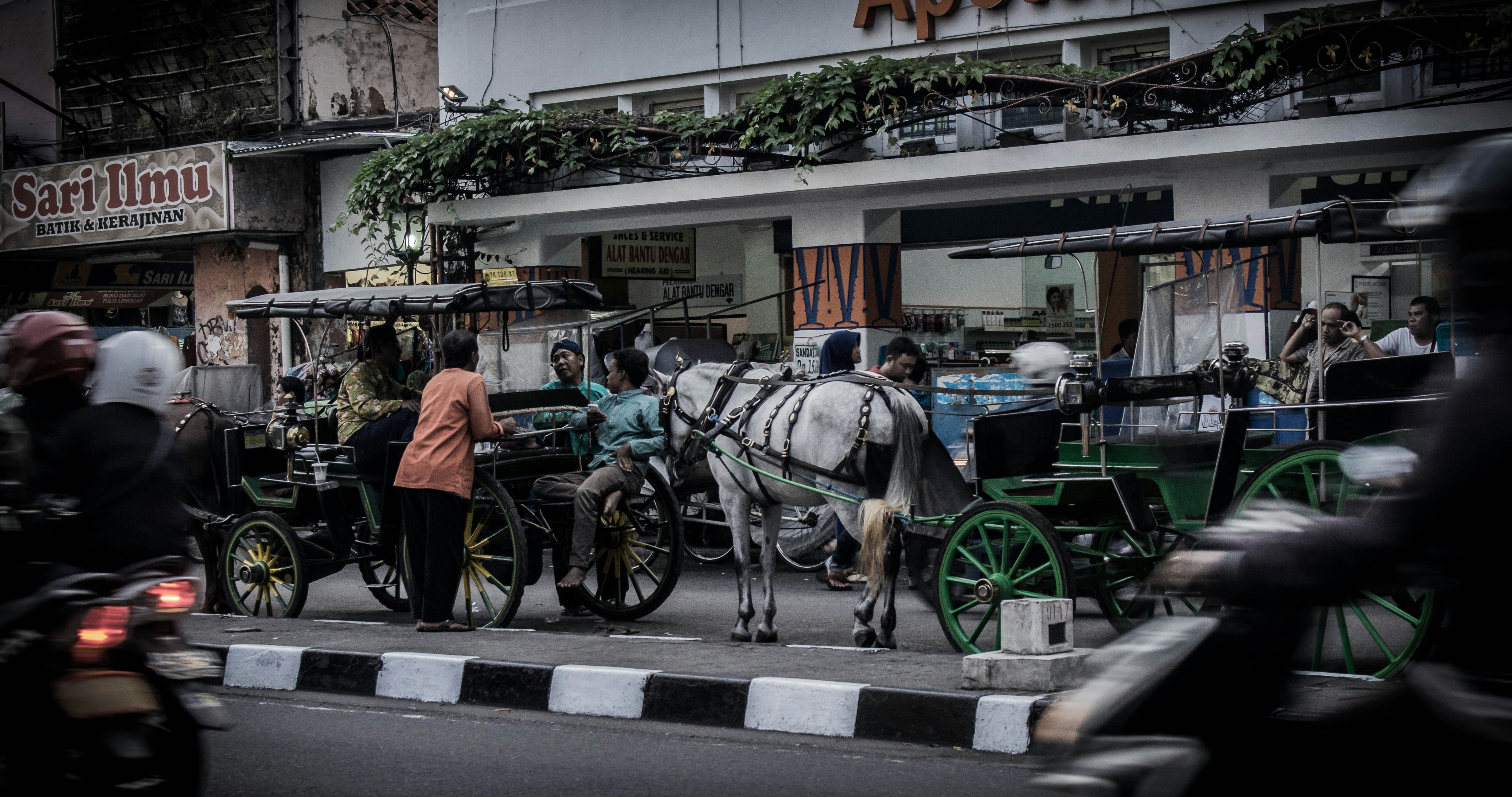 People standing and riding on carriage near store on road during ...
