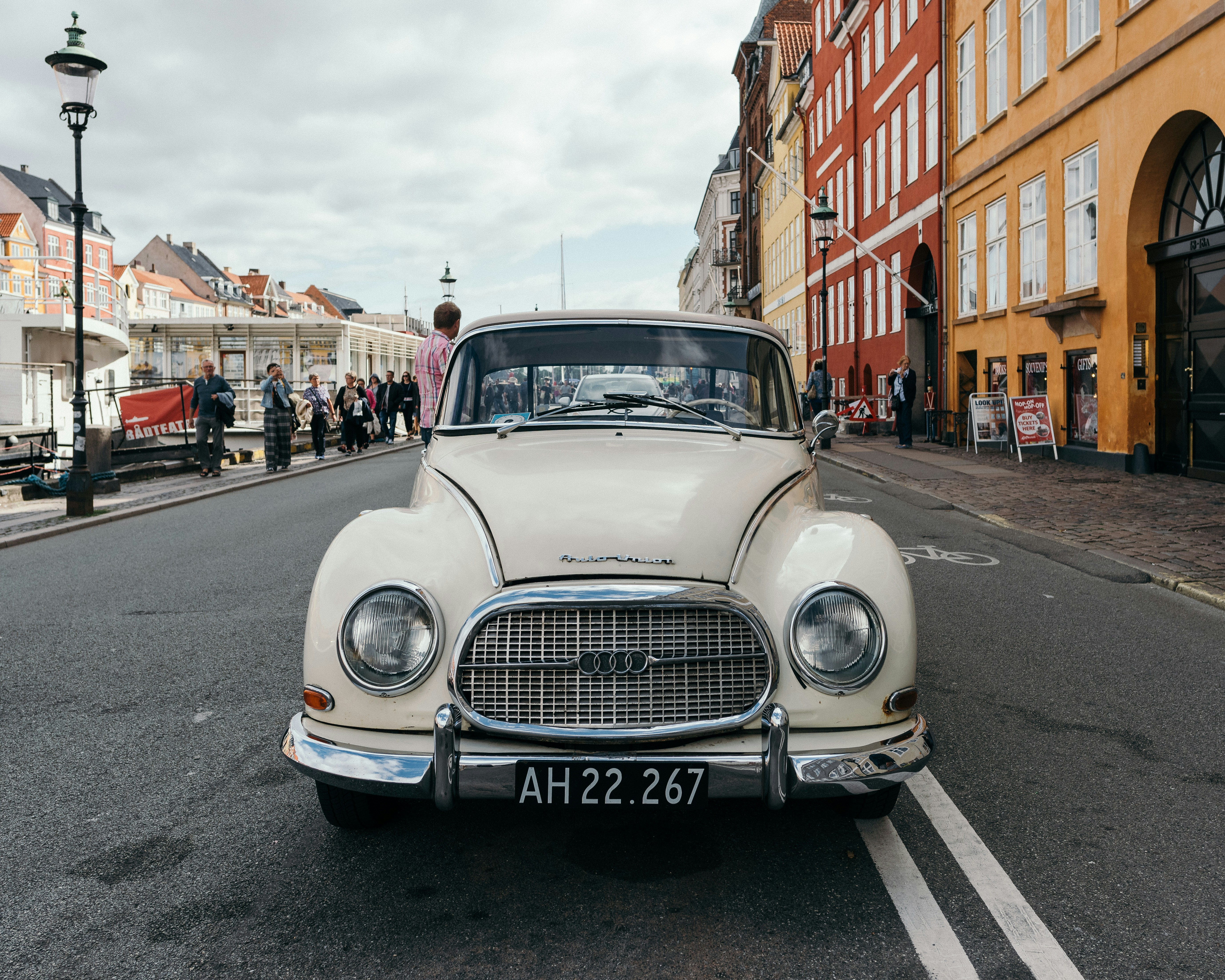 Cream Classic at the Crossroad: A 1950s Sedan Framing a Colorful European Street
