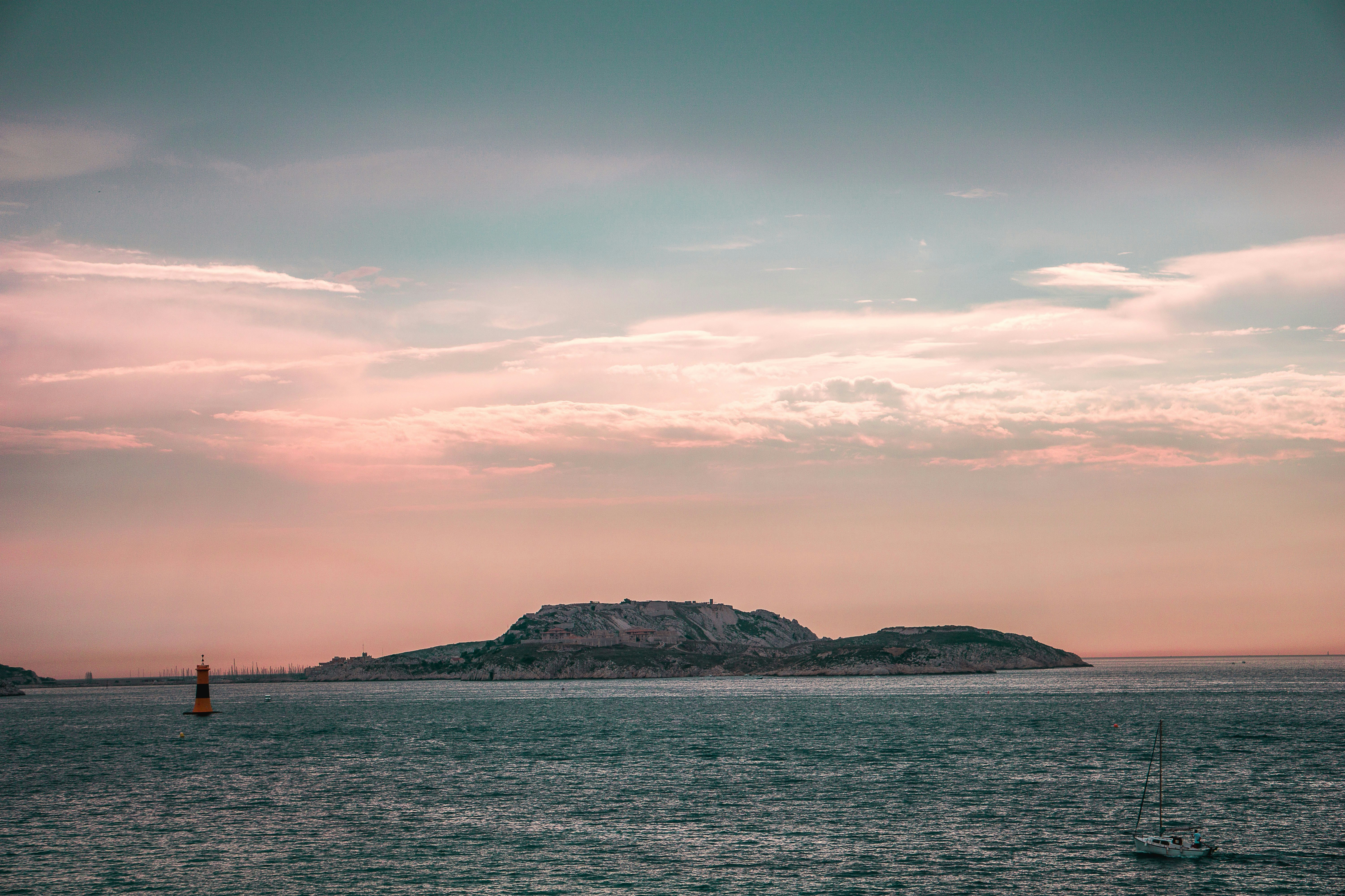 Distant island silhouetted against a pastel-hued sky at sunset.