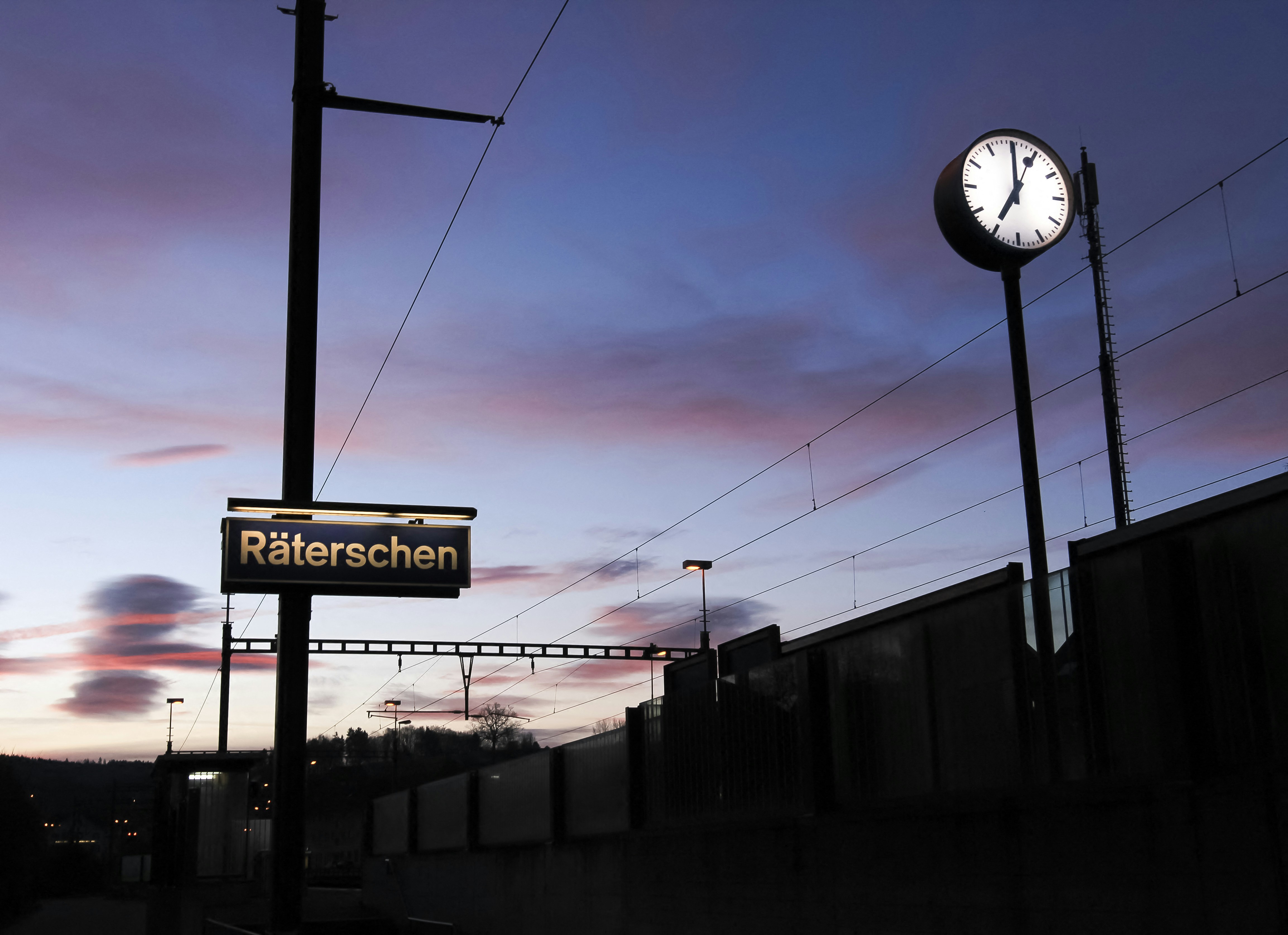 Dusk at Räterschen Station: Clocklight Over Silhouetted Rails