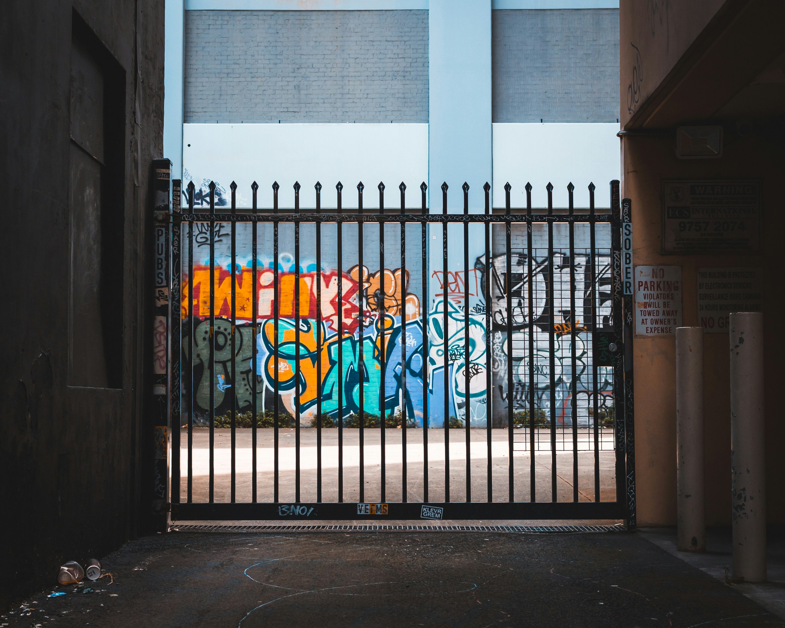 Gated Alleyway Graffiti: Colorful Echoes Beyond Barred Iron