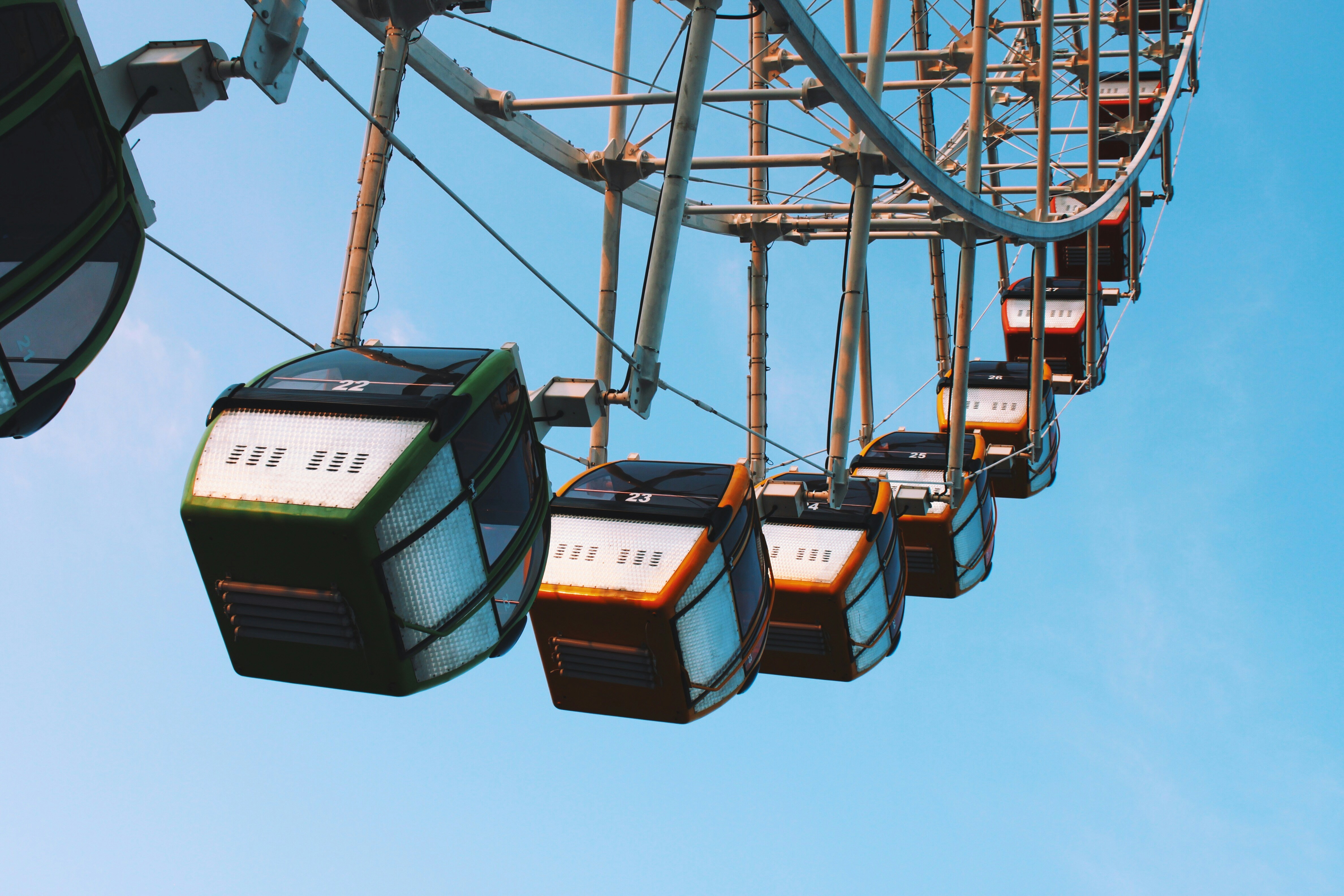 Ferris wheel gondolas rising against a clear blue sky.