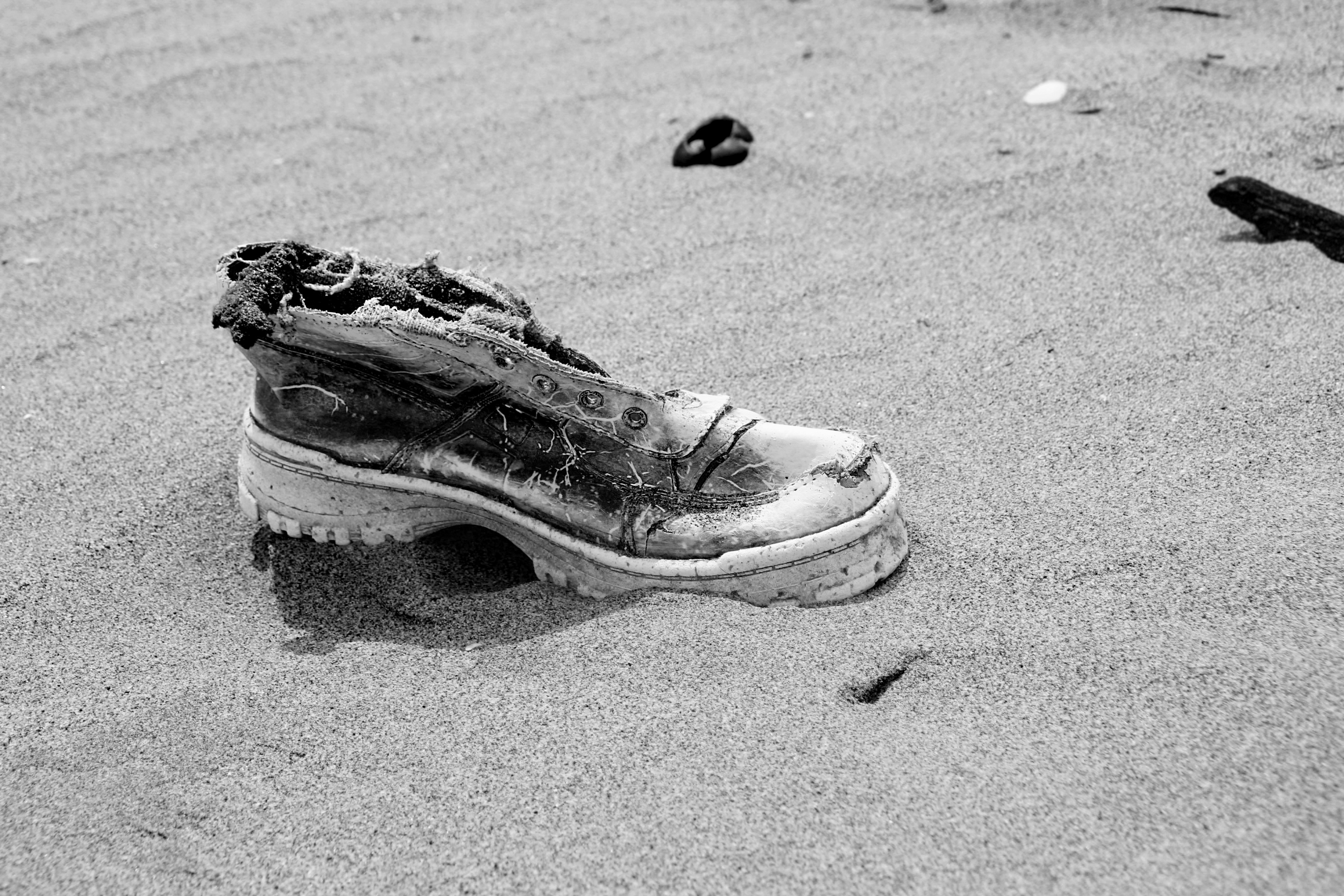 Grayscale photo of unpaired broken boot on sand photo – Free Grey Image ...
