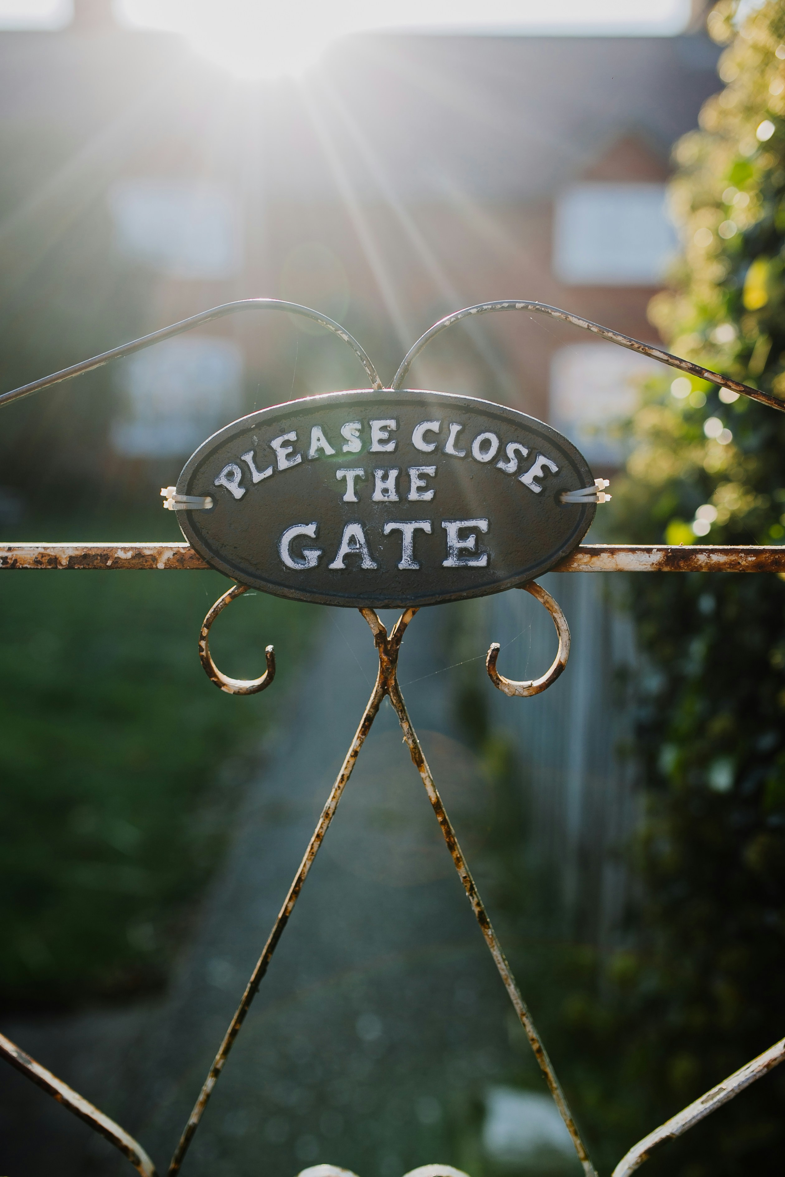 Sunlit Iron Gate Sign: A Quiet Reminder at the Garden Threshold