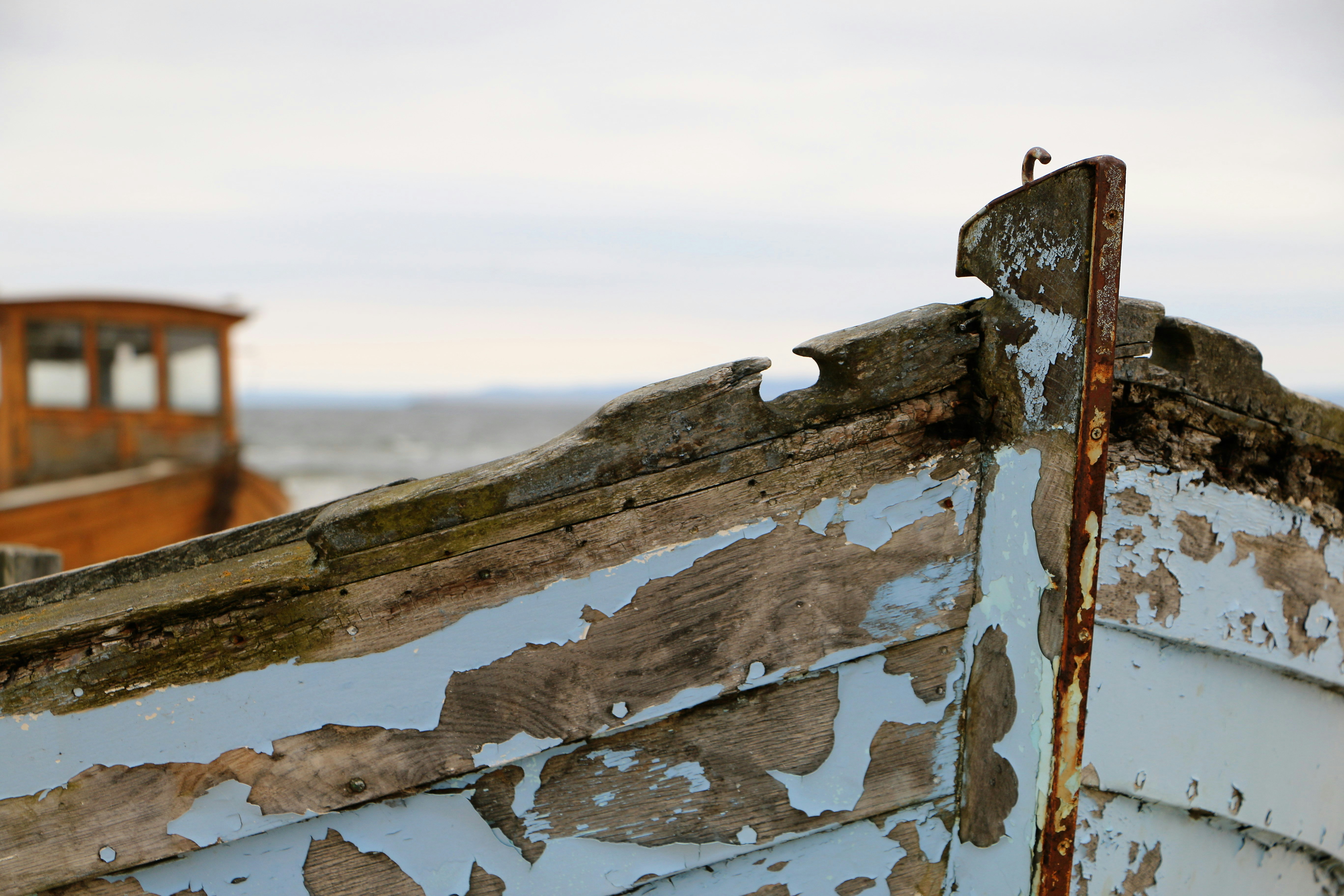 Timeworn Hull: Peeling Blue Paint and Rust Frame a Distant Vessel