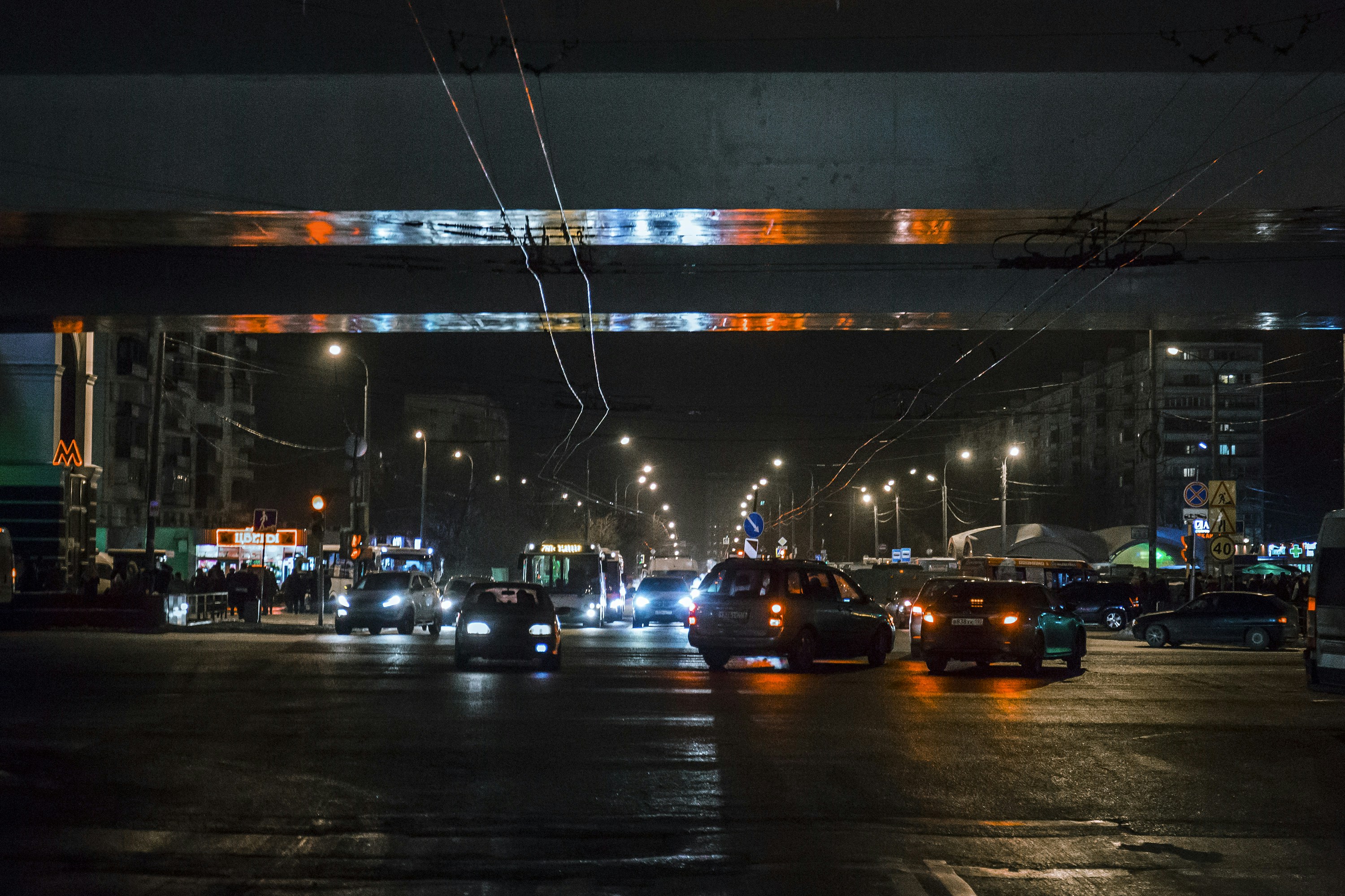 Neon Crossroads Under the Rails: Rain-Slick Night at a City Intersection