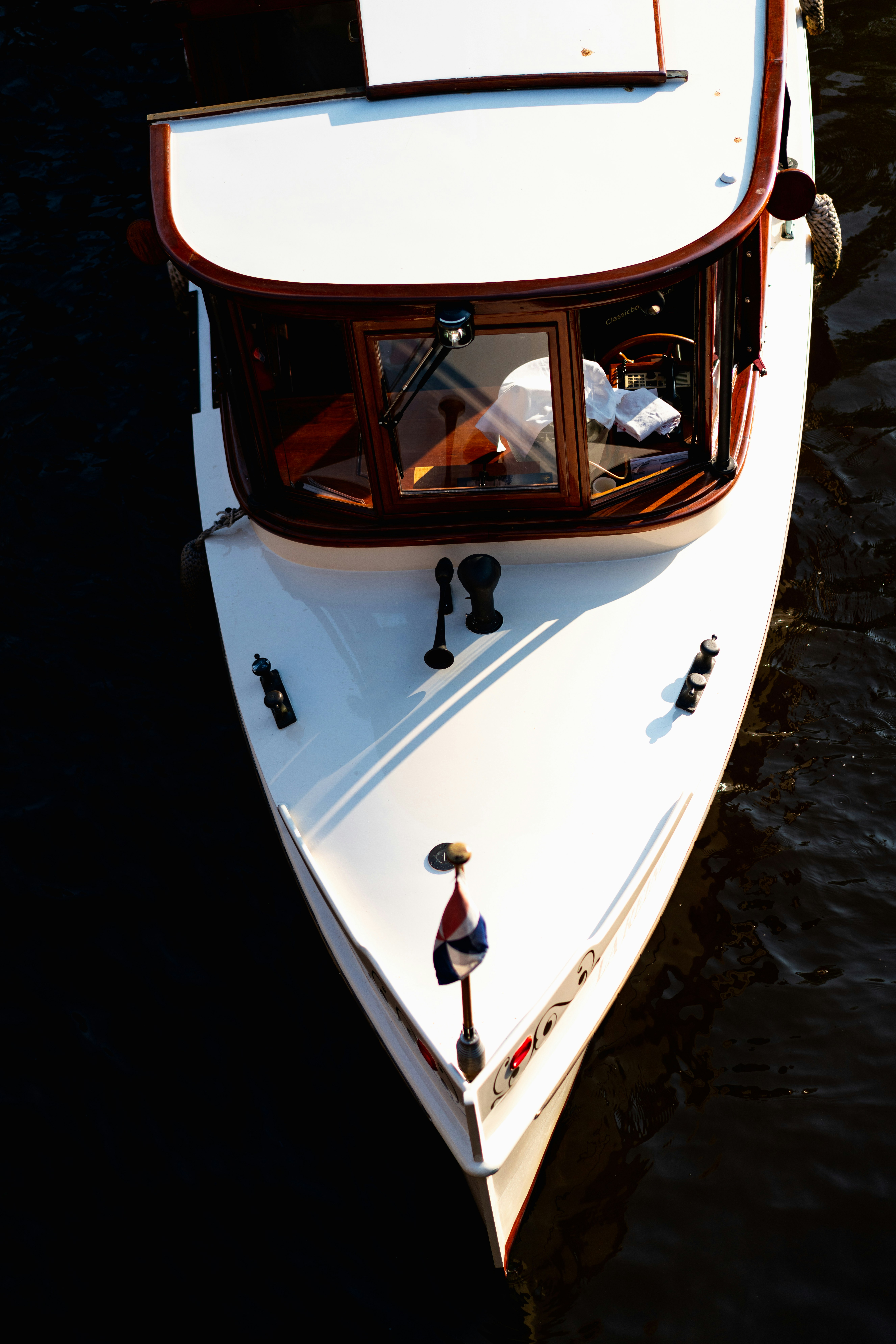 Classic wooden boat with a red-trimmed cabin cruising on dark waters, captured from above.