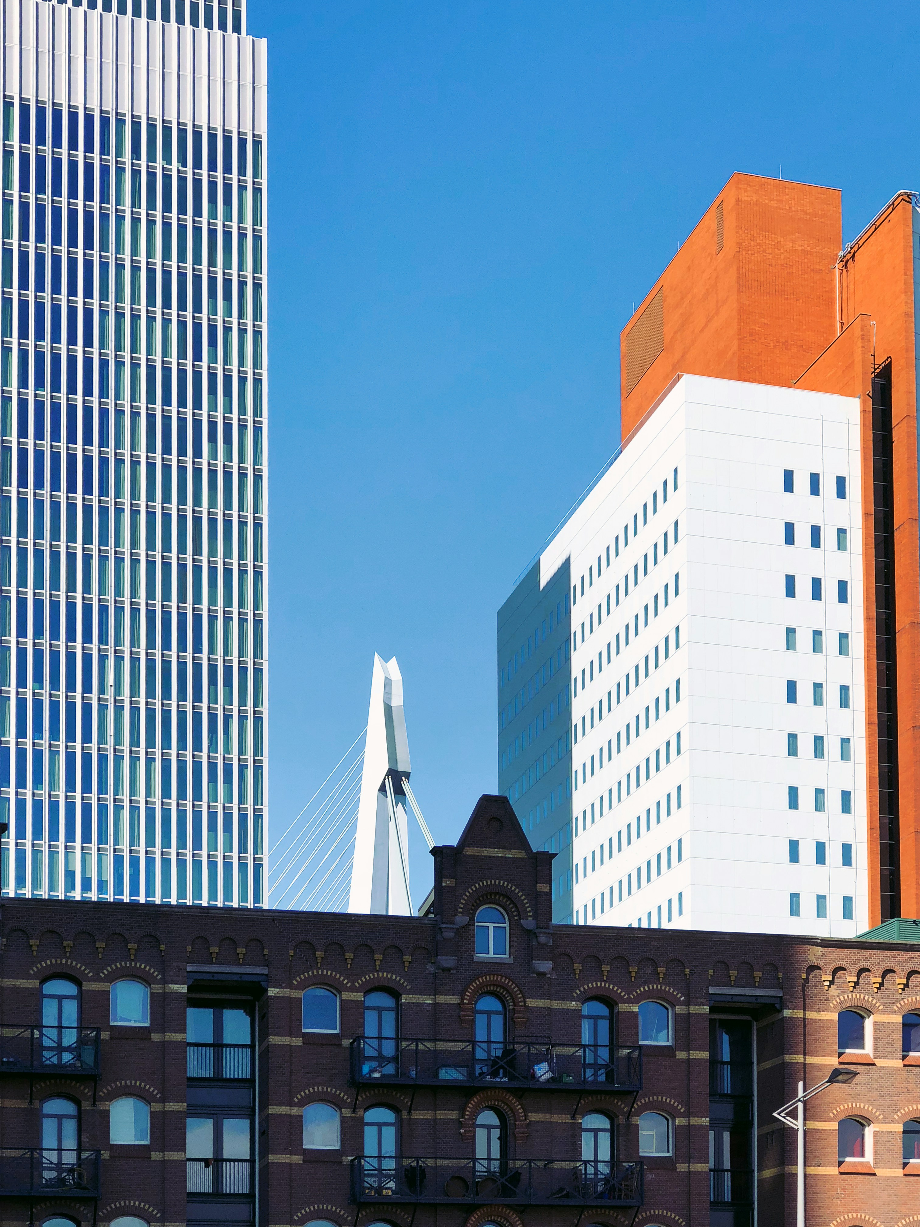 A blend of contemporary skyscrapers and historical buildings showcases urban architectural diversity against a clear blue sky.