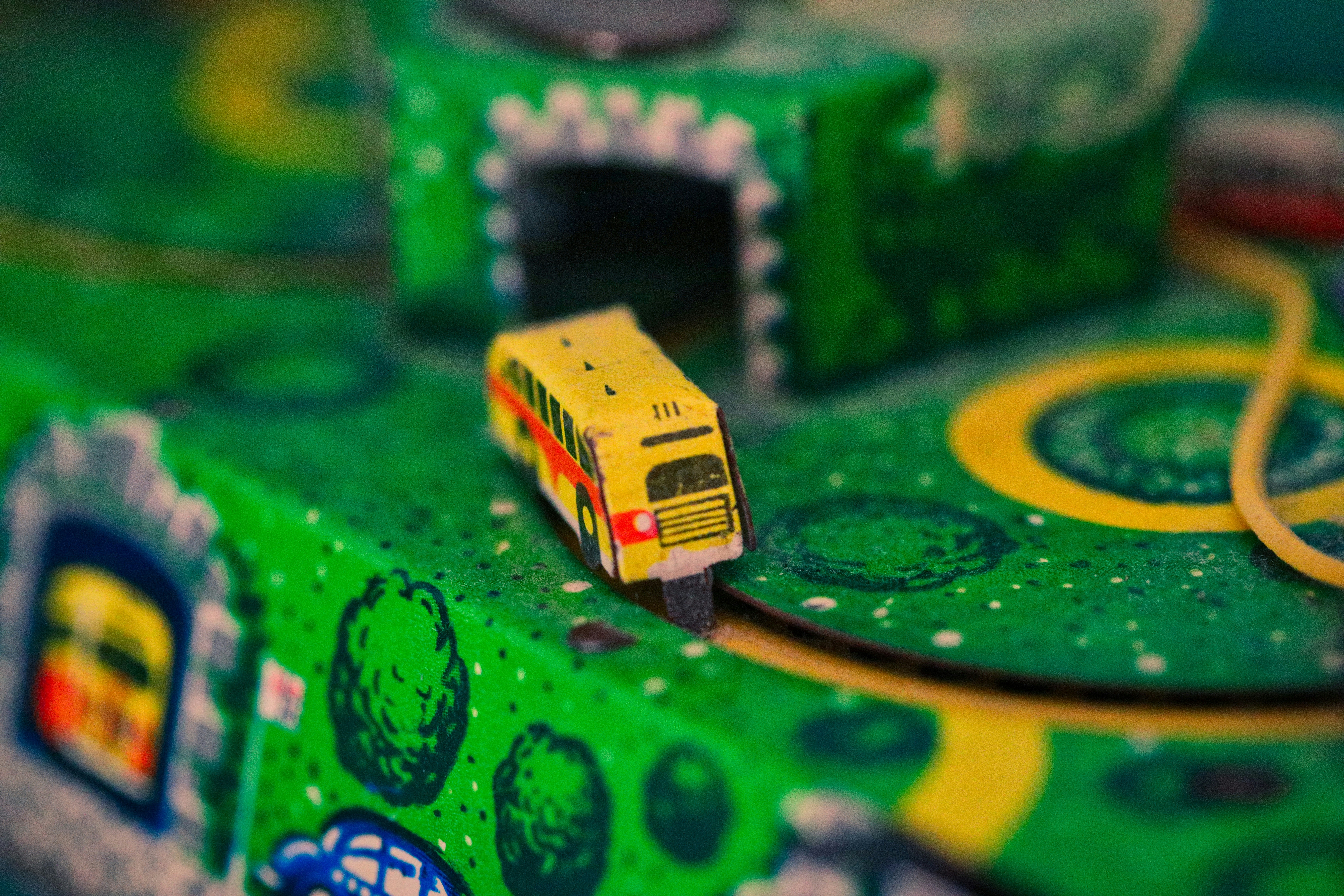 A vibrant toy bus navigating a colorful, illustrated landscape filled with playful designs and patterns.