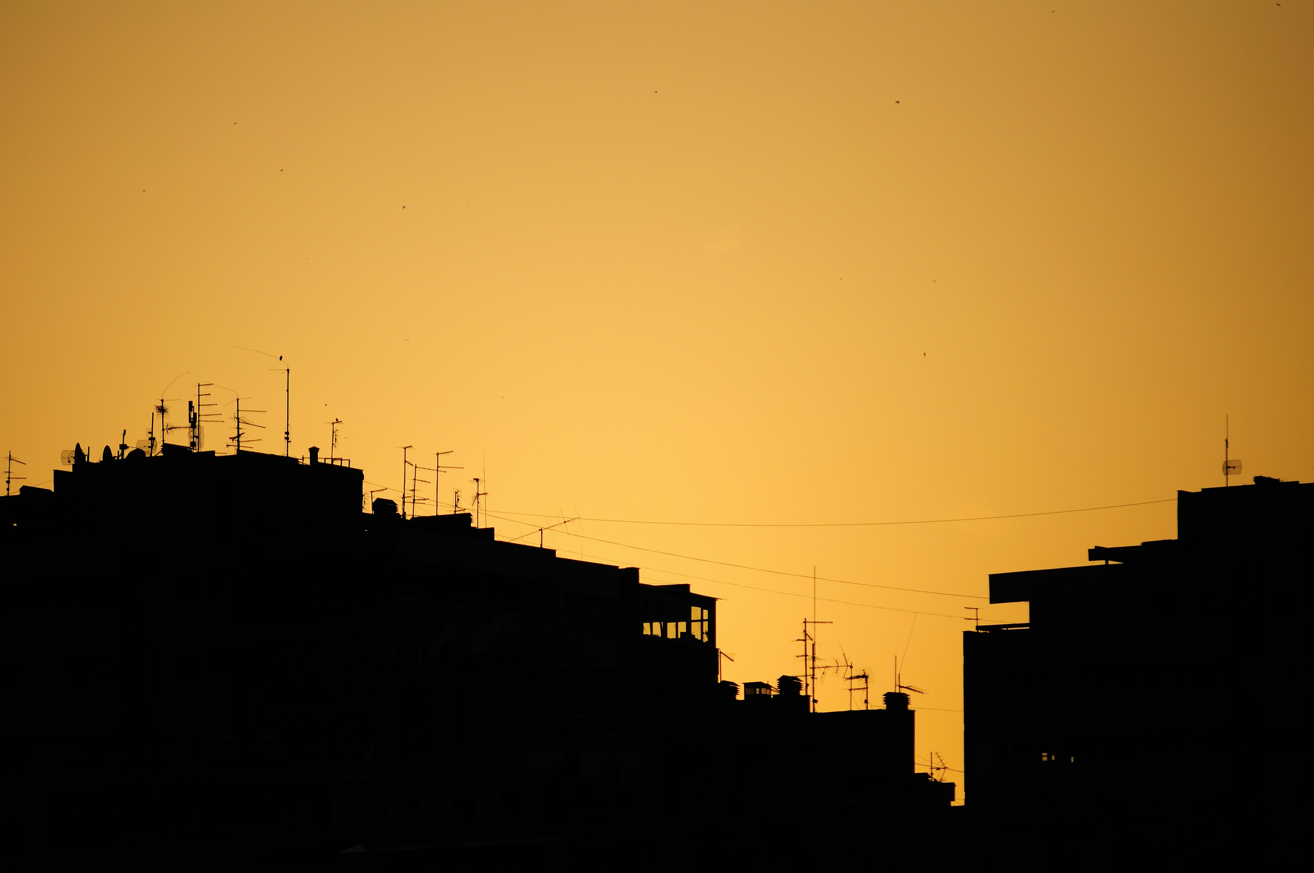 Silhouette of city buildings against a warm, golden sunset sky.