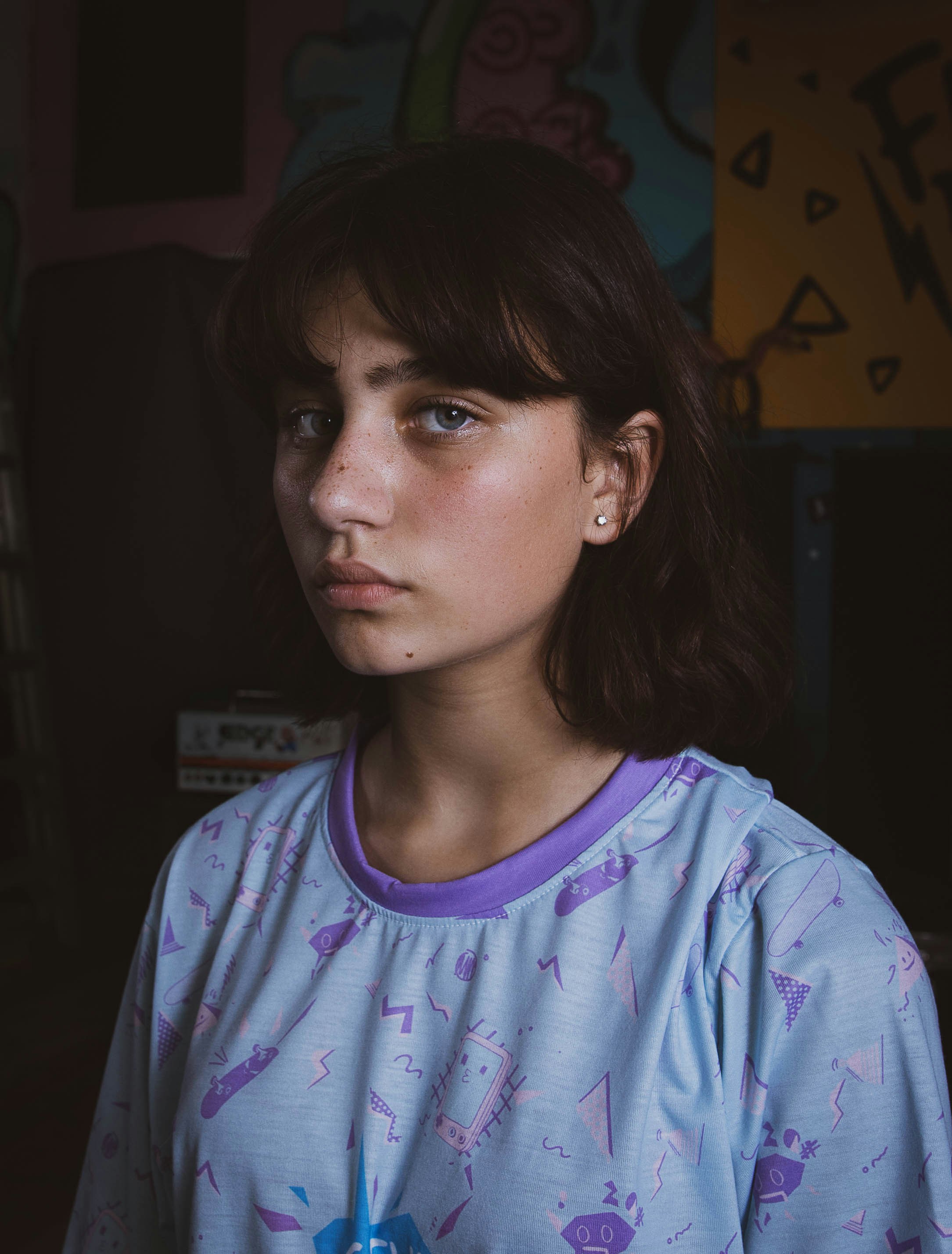 A young girl with a serious expression poses against a vibrant, abstract background, showcasing her unique style and personality.
