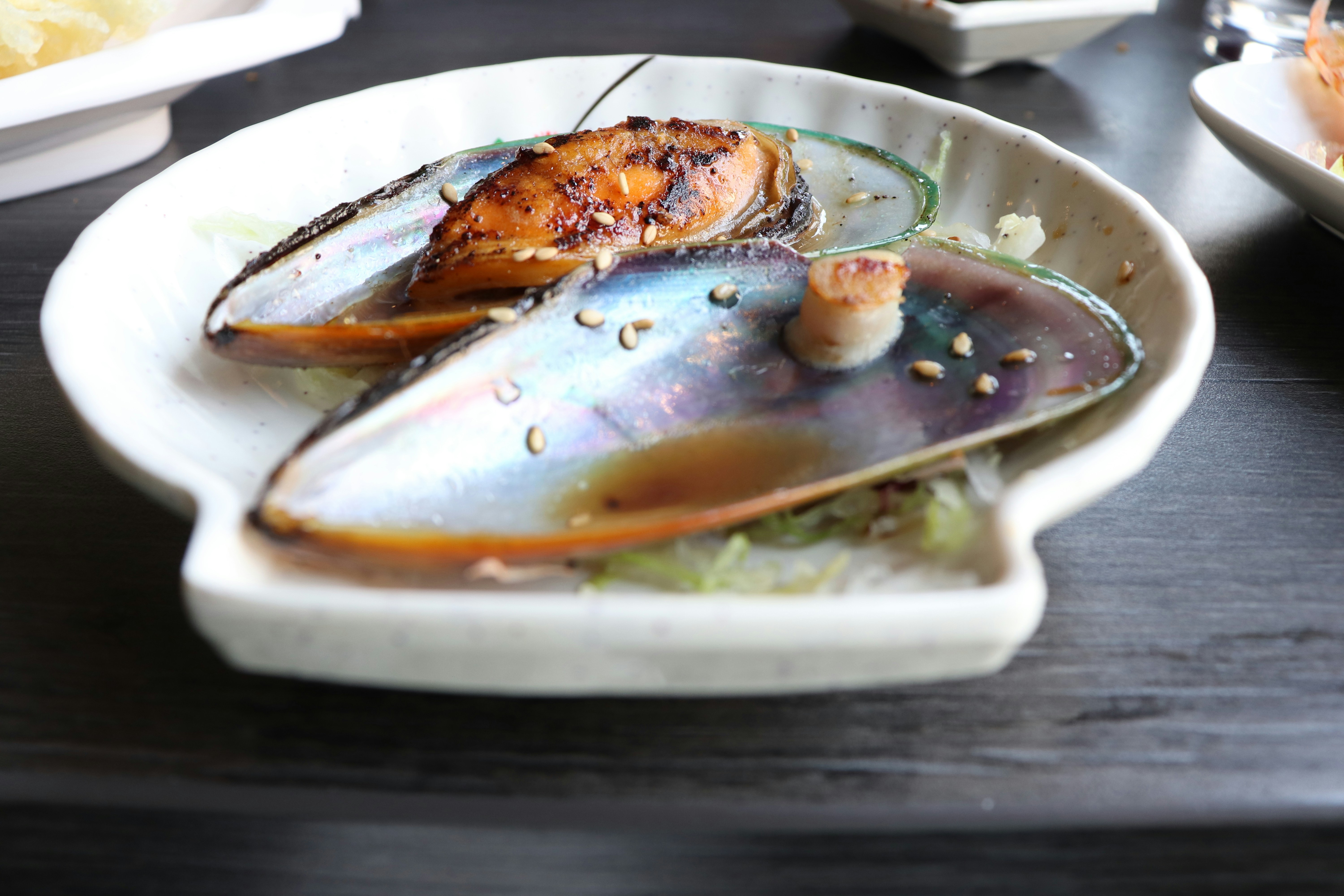 Two mussels in a rich sauce served on a ceramic dish.