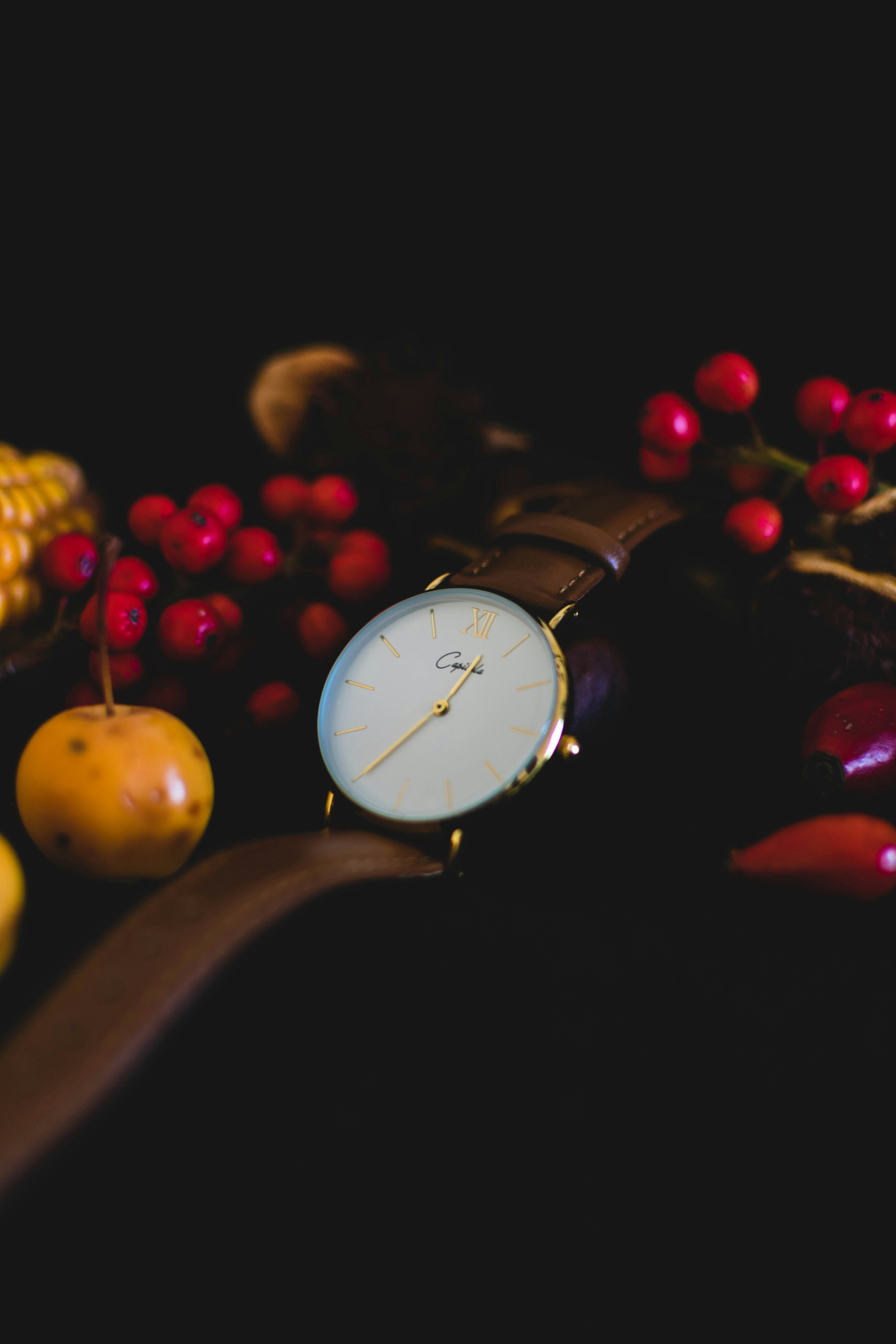 Timeless Tick: a gold-banded wristwatch resting among red berries and fruit chords