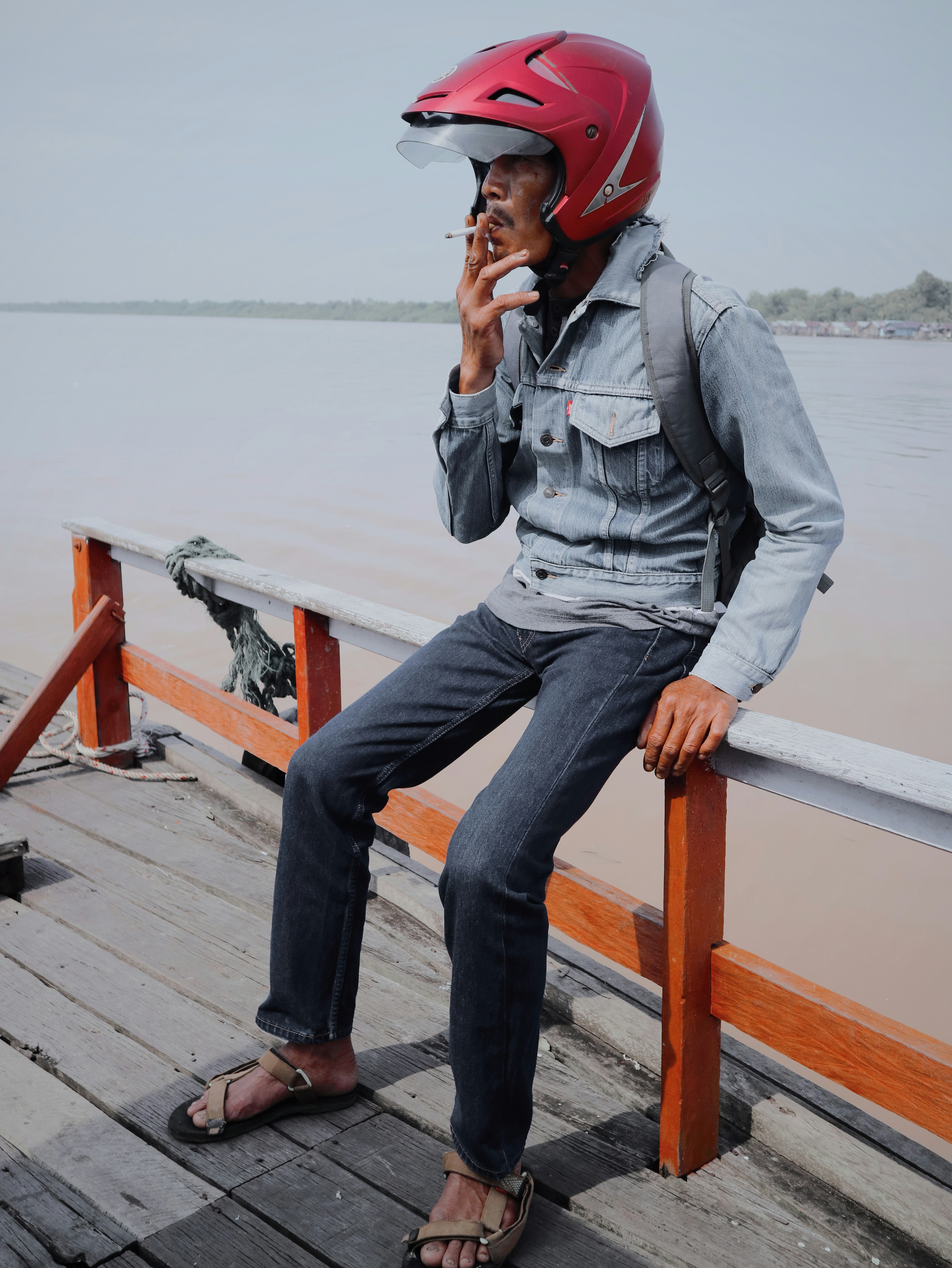 Rider on the Pier: Quiet Moment Beneath a Red Helmet