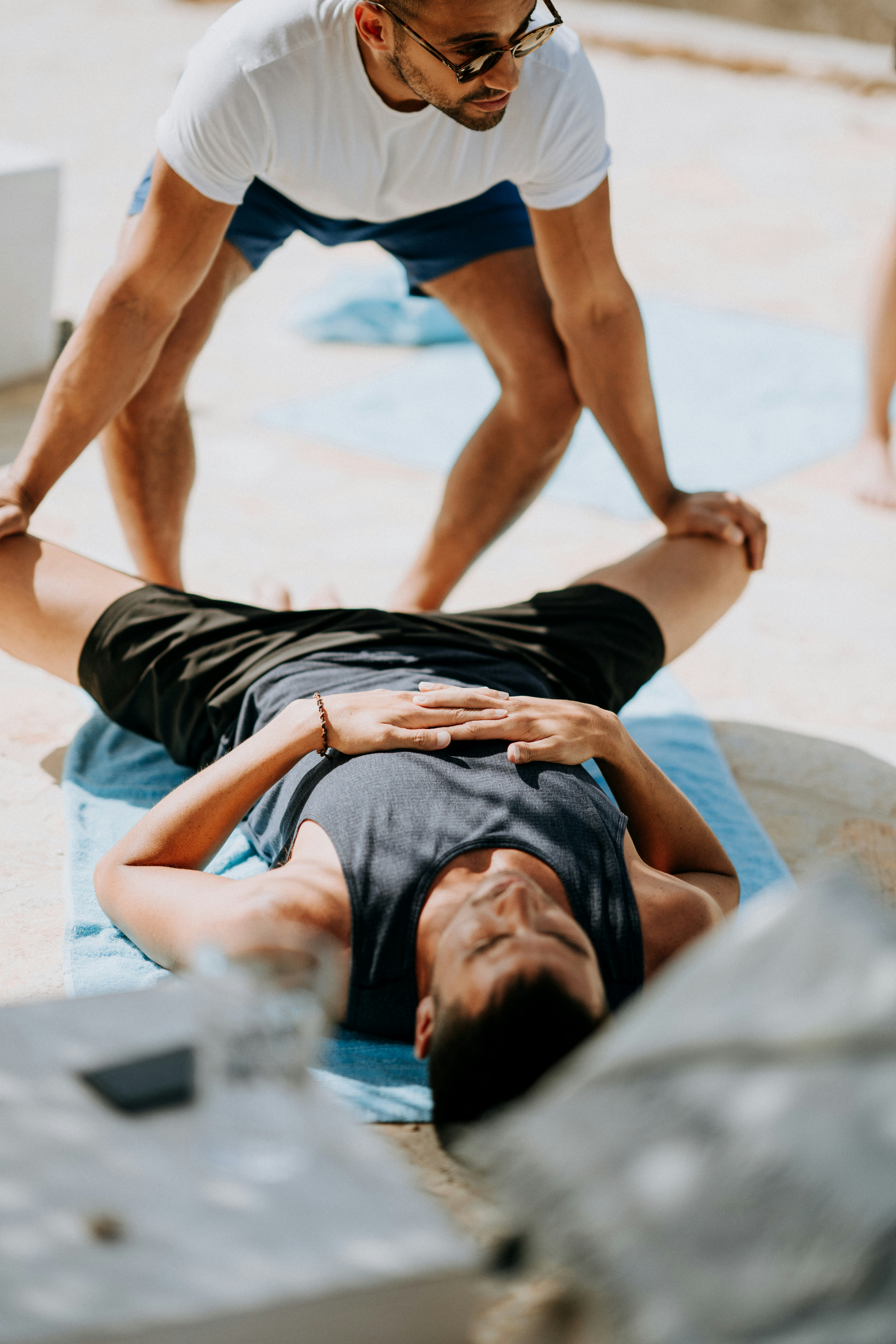 Two individuals engaged in a stretching session on a sunny day, emphasizing wellness and relaxation.