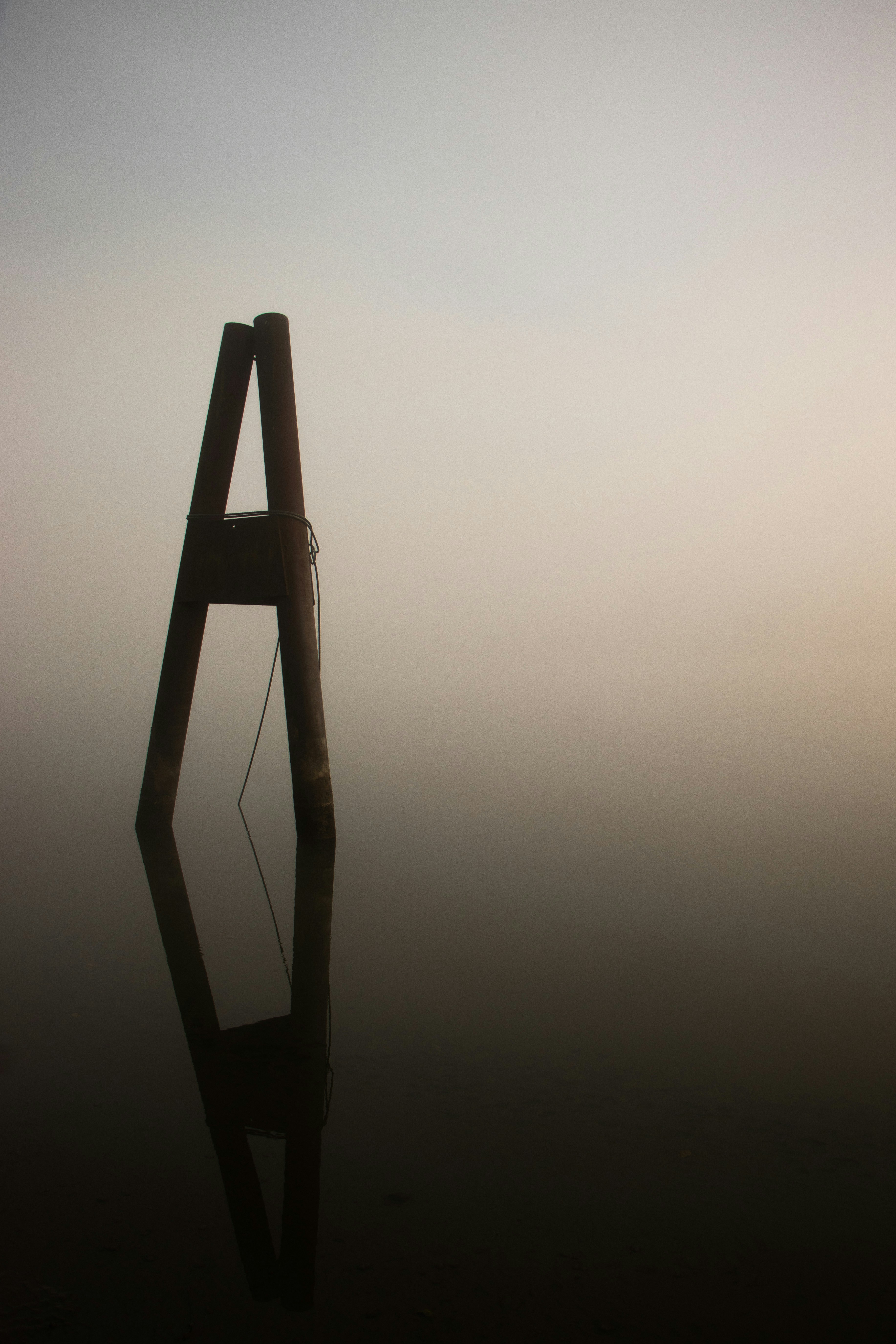 Out one morning taking photos I cam across a A-framed pillar sticking out of the water. Next to zero water movement. With the fog it looked like a solitary figure amidst nothing surrounding it.