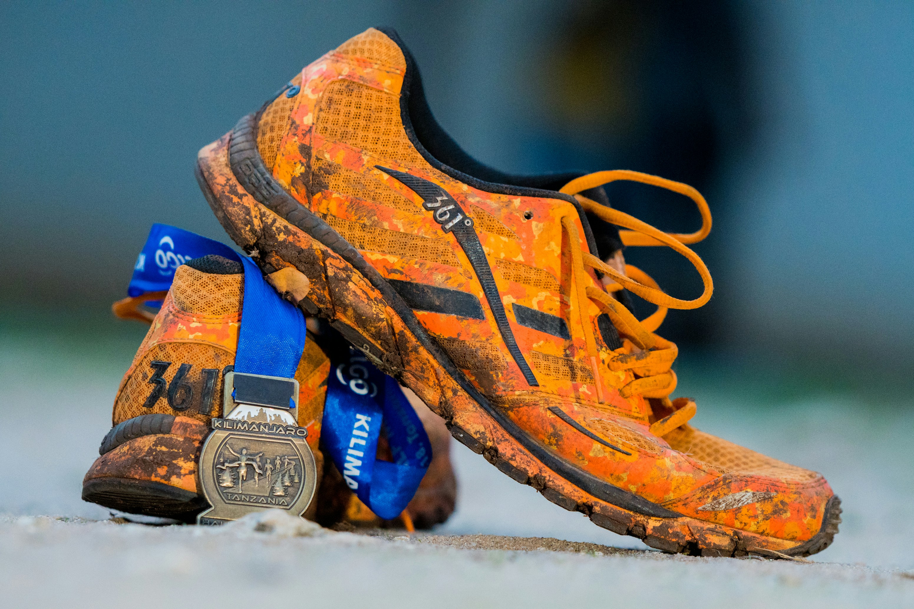 Mud-Streaked Triumph: An Orange Trail Shoe Paired with a Finisher's Medal