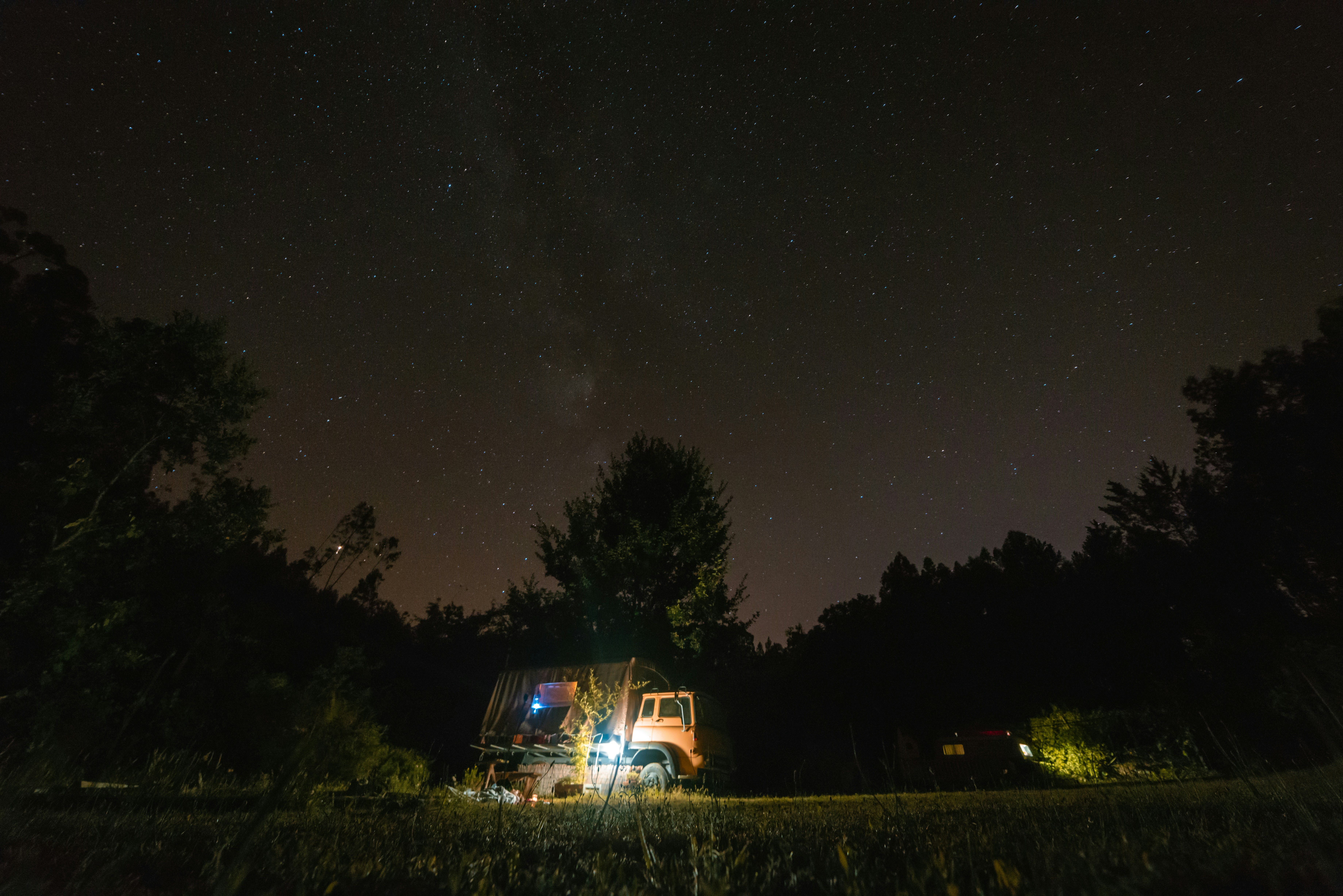 Under the Milky Veil: A Truck's Glow Beneath a Starfield