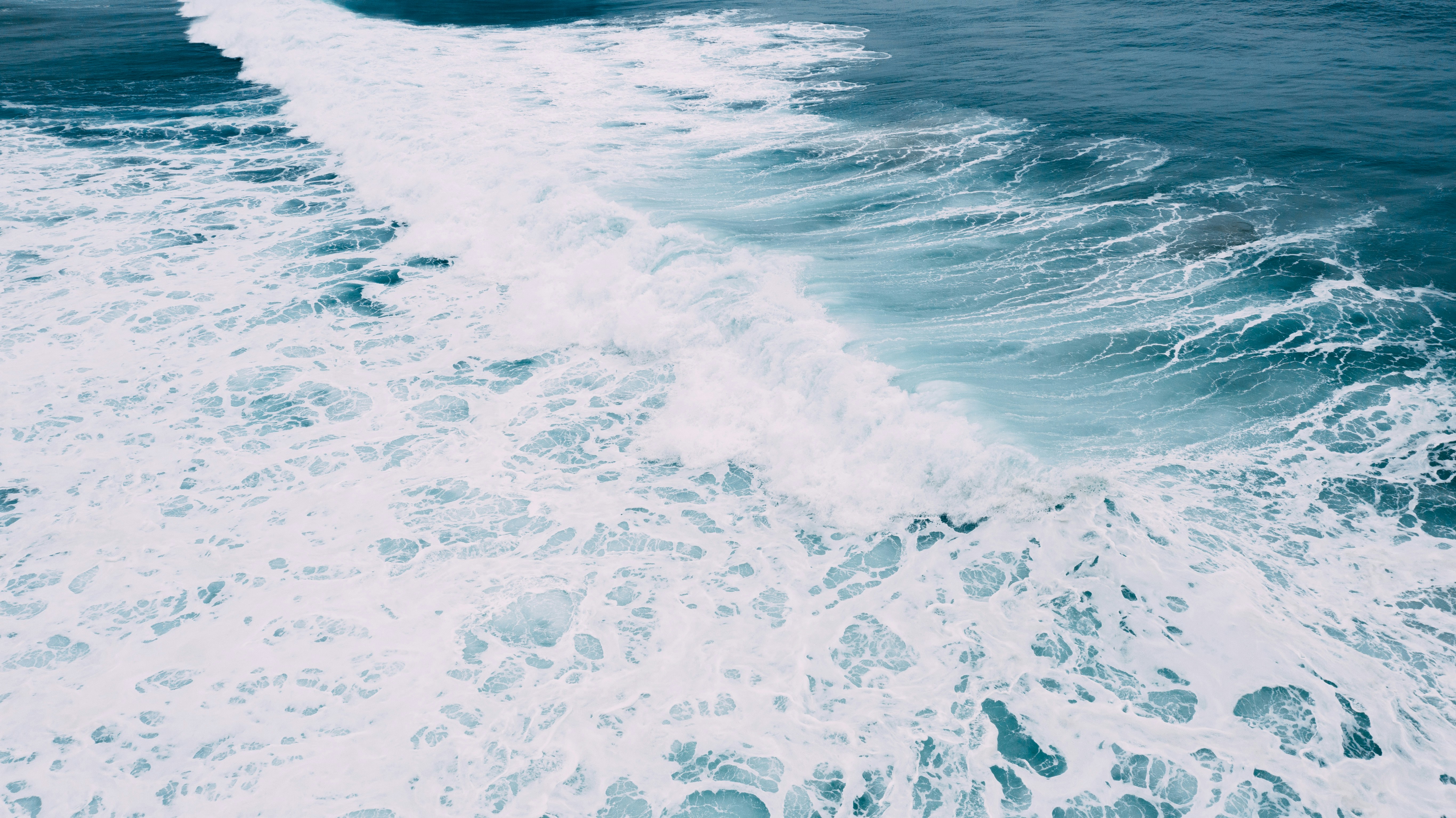 Aerial view of foamy waves crashing against the shoreline at Tunnel Beach in New Zealand.
