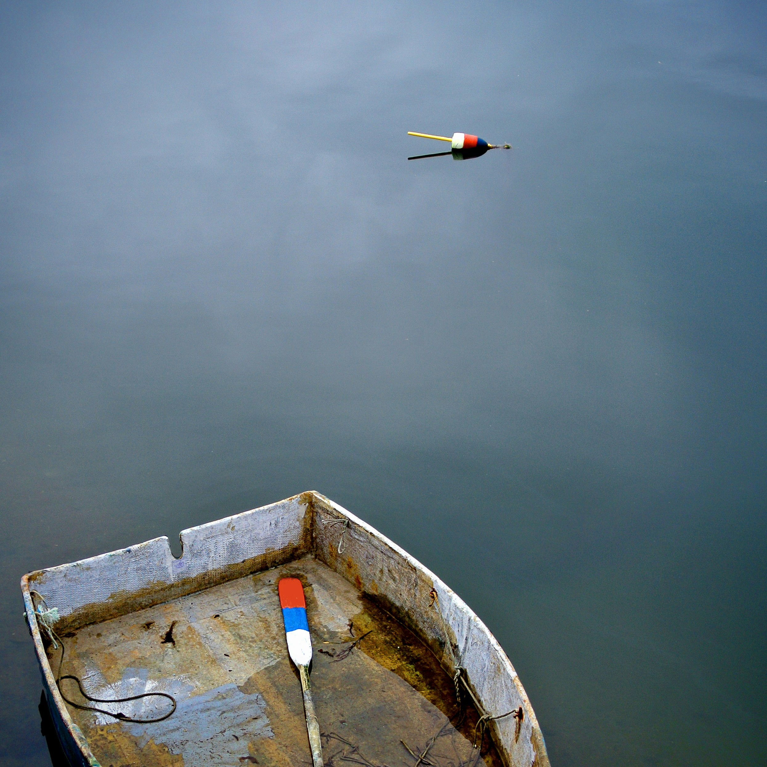 Rockport Harbour is about an hour north of Boston and a delightful little place. I thoroughly recommend eating lobster from the harbourside cafes. I snapped this whilst travelling, I hadn’t got my dSLR with me but had brought my daughters Nikon J2. 
The tones in the water are what I like best about the picture. The sky and the light was otherwise flat and I wasn’t too hopeful of getting any decent pictures, especially as I normally gravitate towards bright contrast and colour, but this turned out to be pretty good.