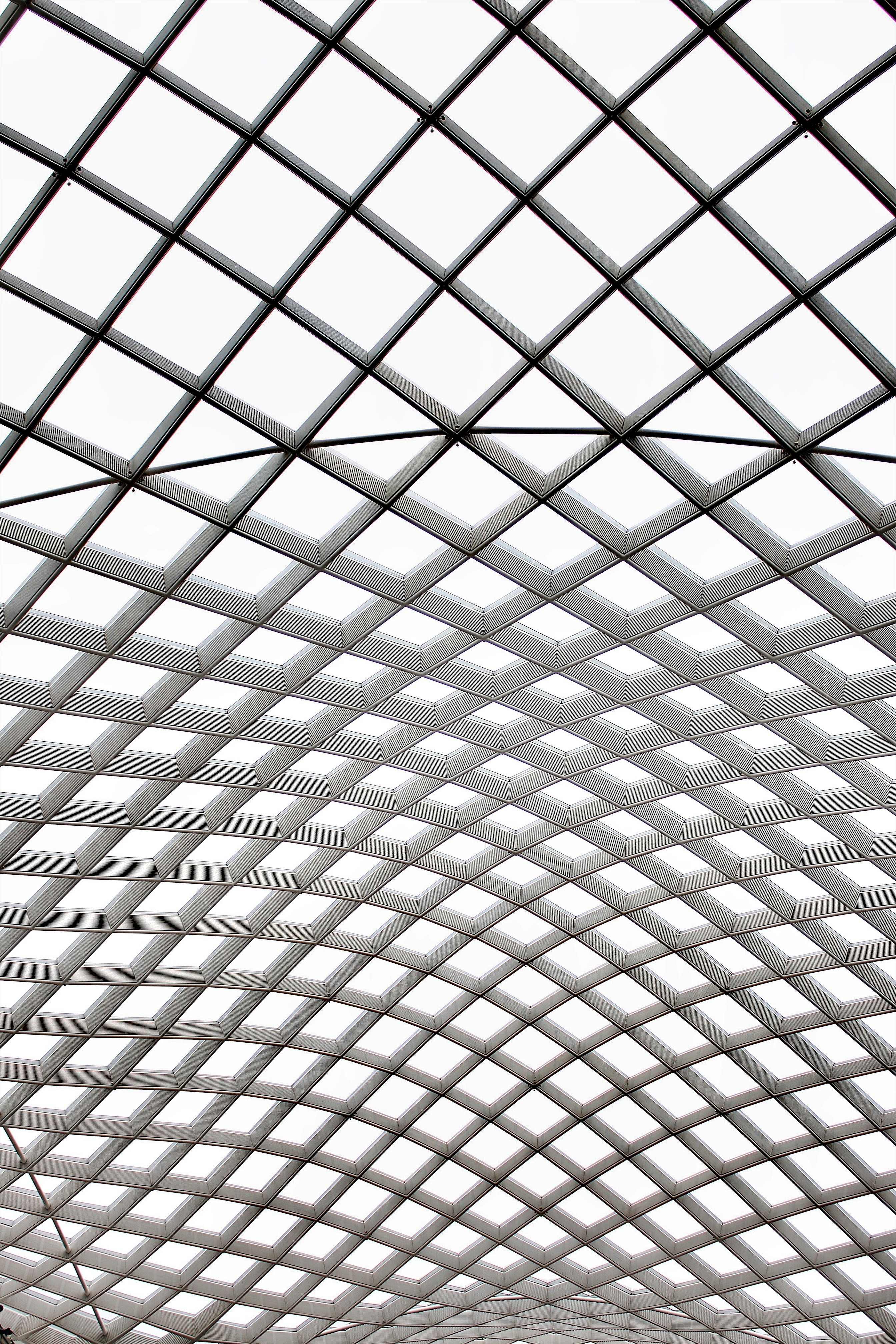 Intricate grid pattern of a modern architectural canopy, showcasing a blend of light and shadow. The design emphasizes symmetry and structure.