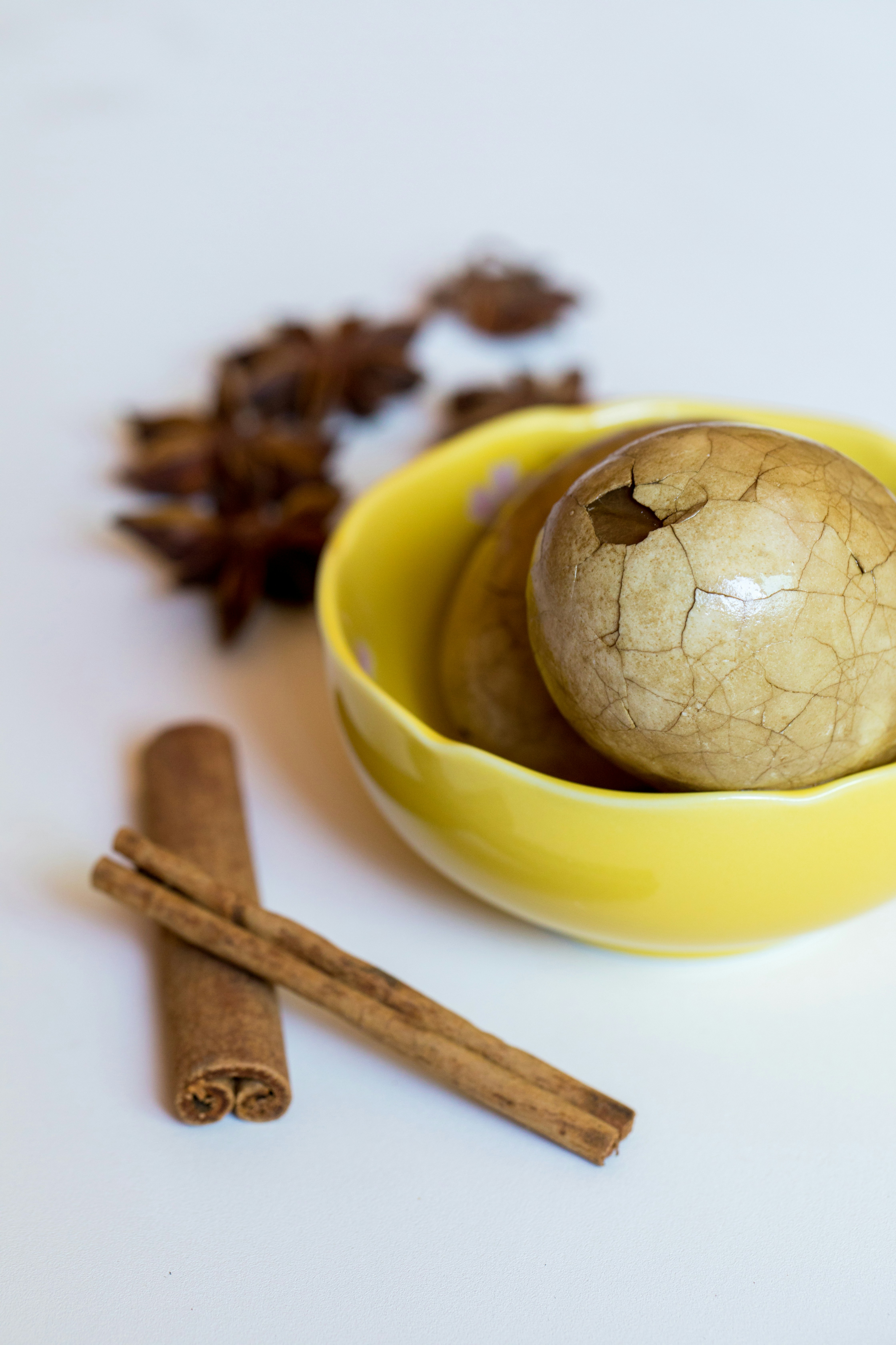 Cracked Globe in a Sunlit Yellow Bowl, Framed by Cinnamon and Star Anise
