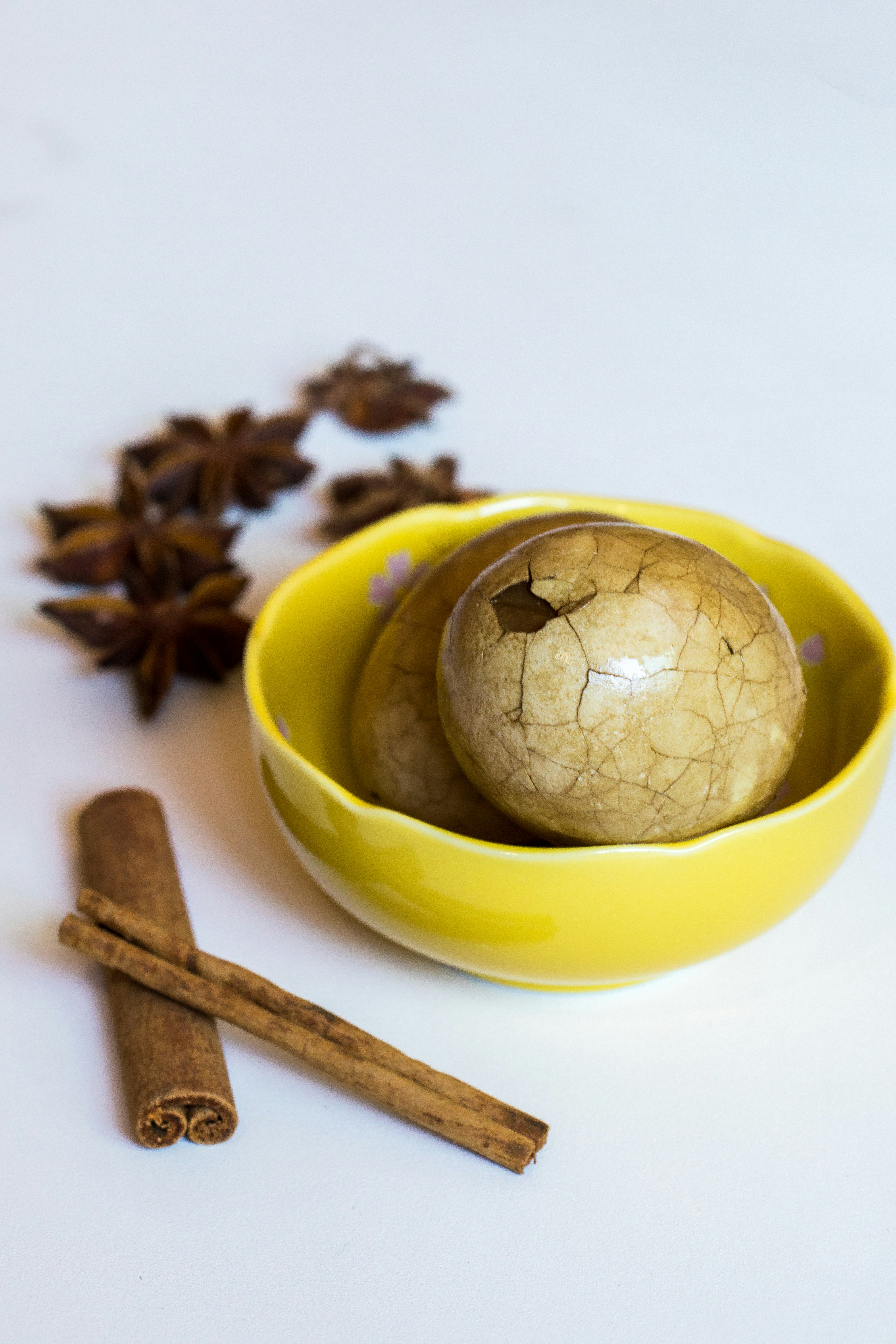 Cracked porcelain spheres nestled in a sunlit yellow bowl