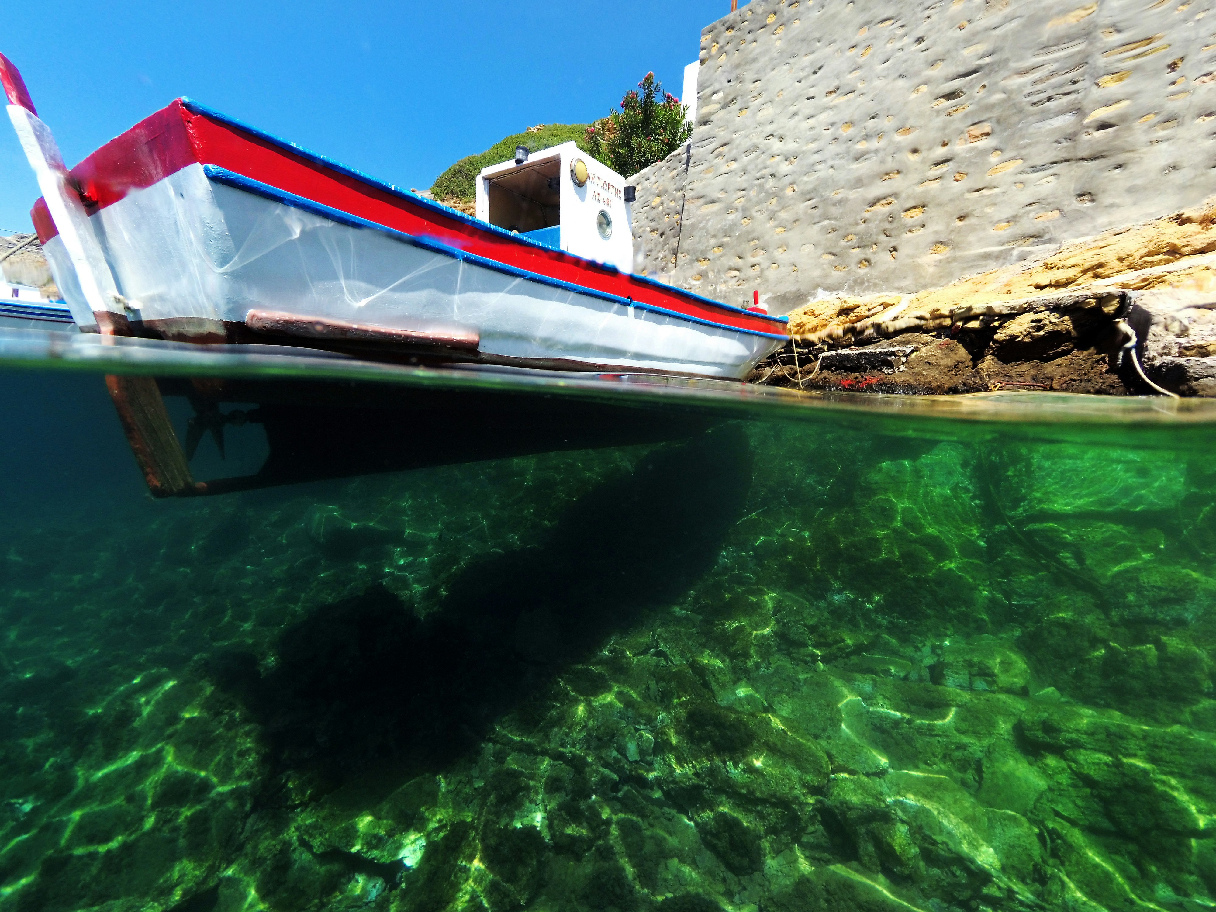 Crimson-Trimmed Boat at the Emerald Edge of a Stone Quay