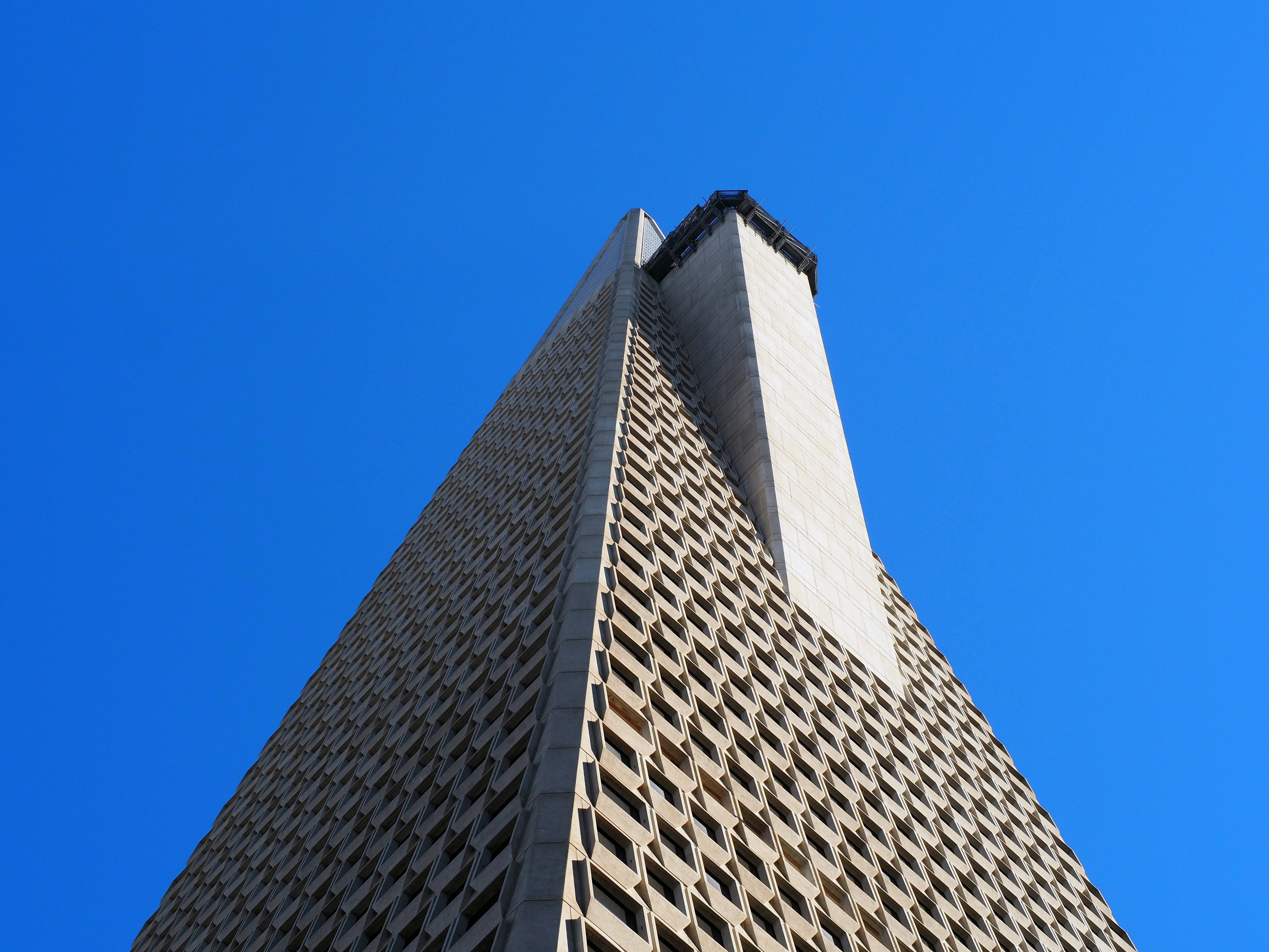 Apex Above the Grid: Low-Angle Portrait of a Latticed Skyscraper Against a Cobalt Sky