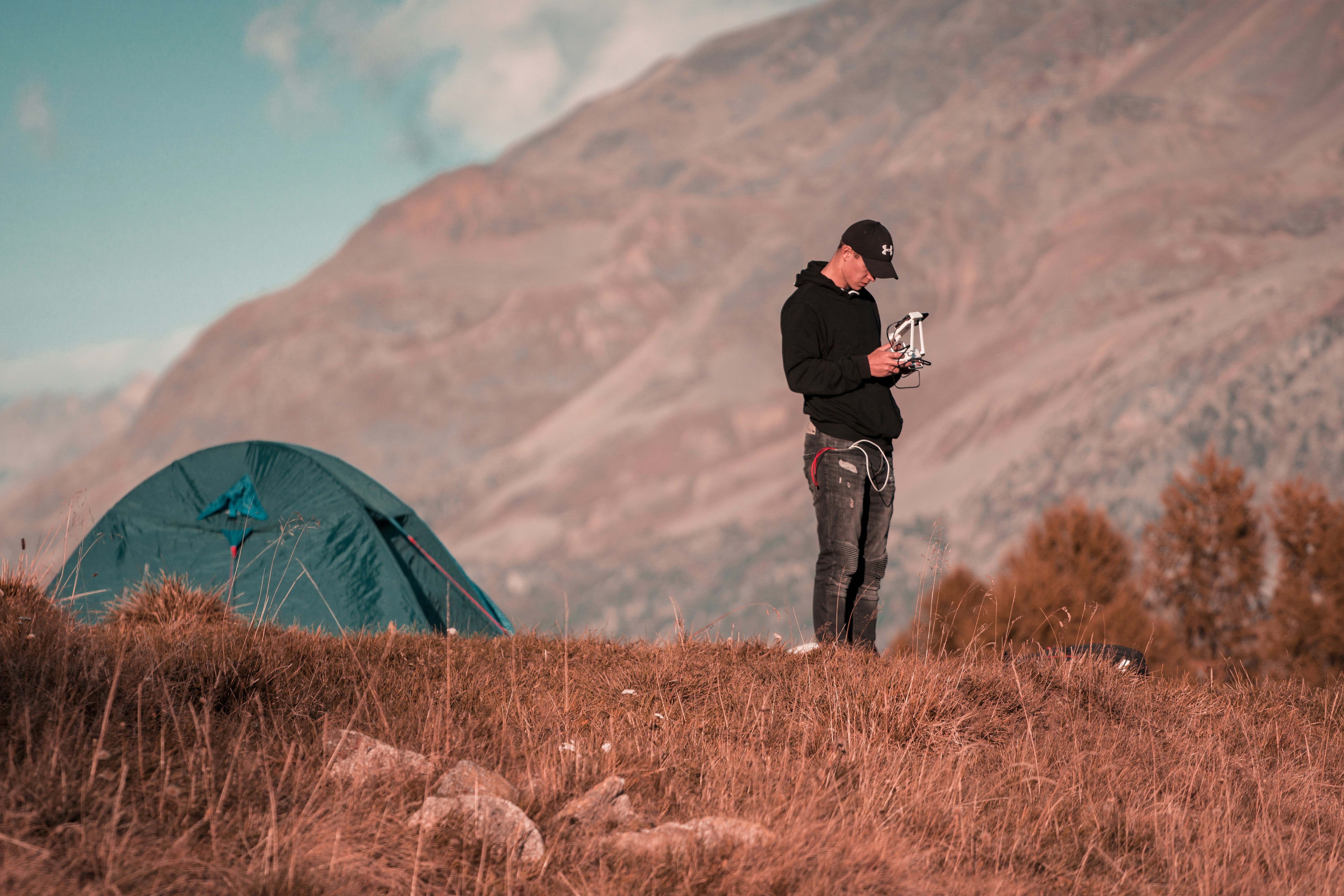 Remote Peaktop Operator: A Solo Scout with Drone Controller by a Tented Camp