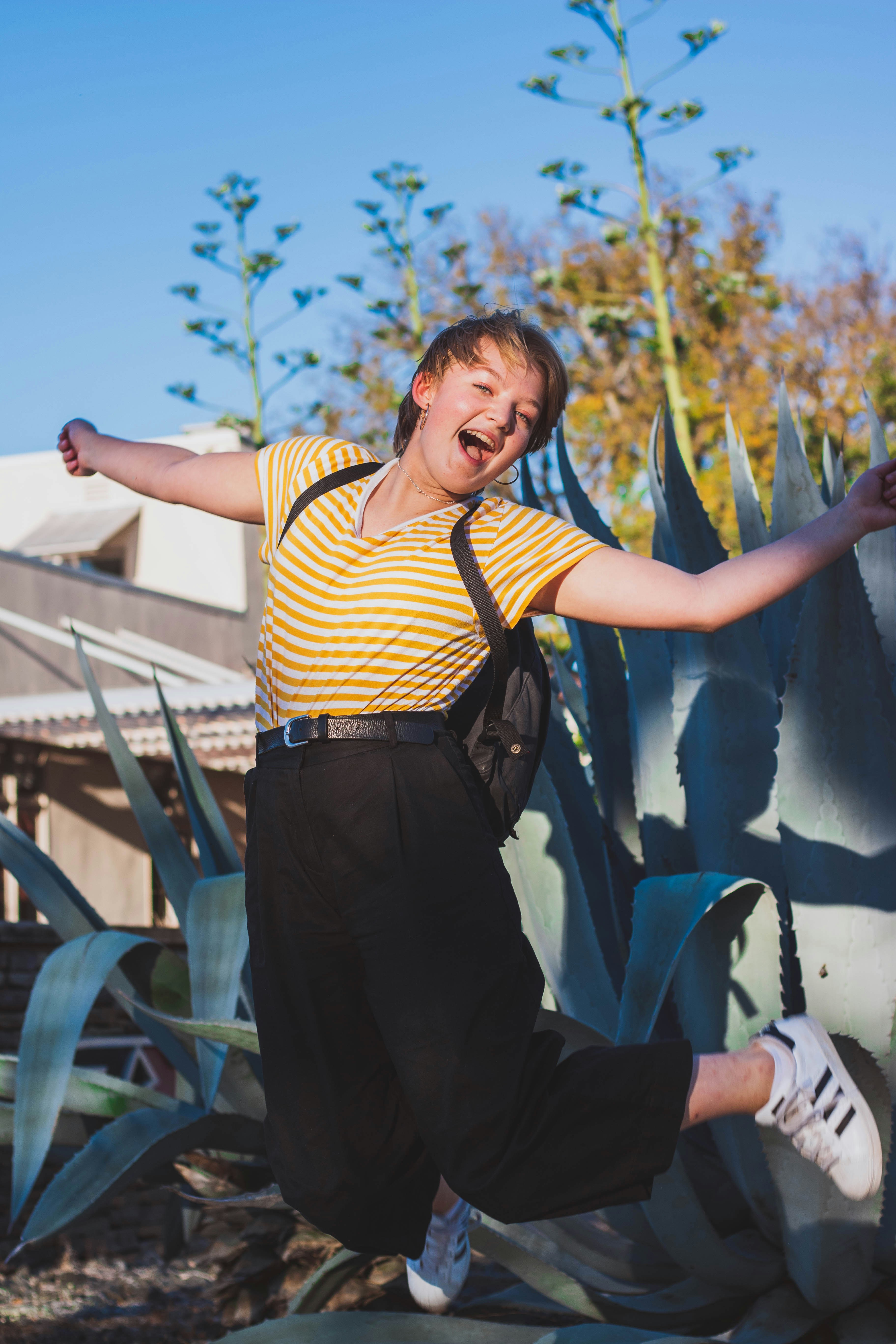 Woman wearing yellow-and-white striped blouse jumping mid air photo ...