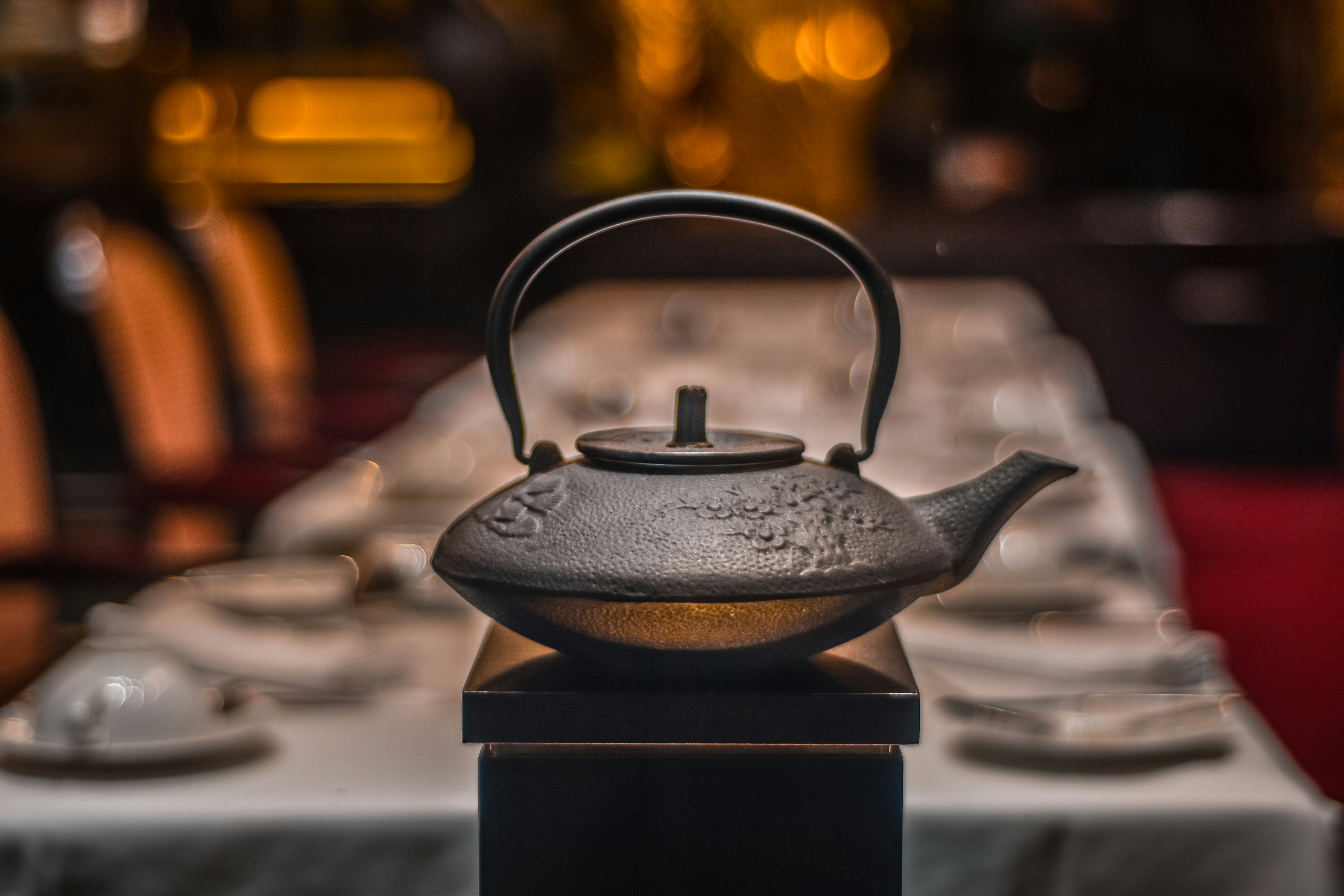 Teapot on a Pedestal: Quiet Spotlight in a Dim Dining Hall