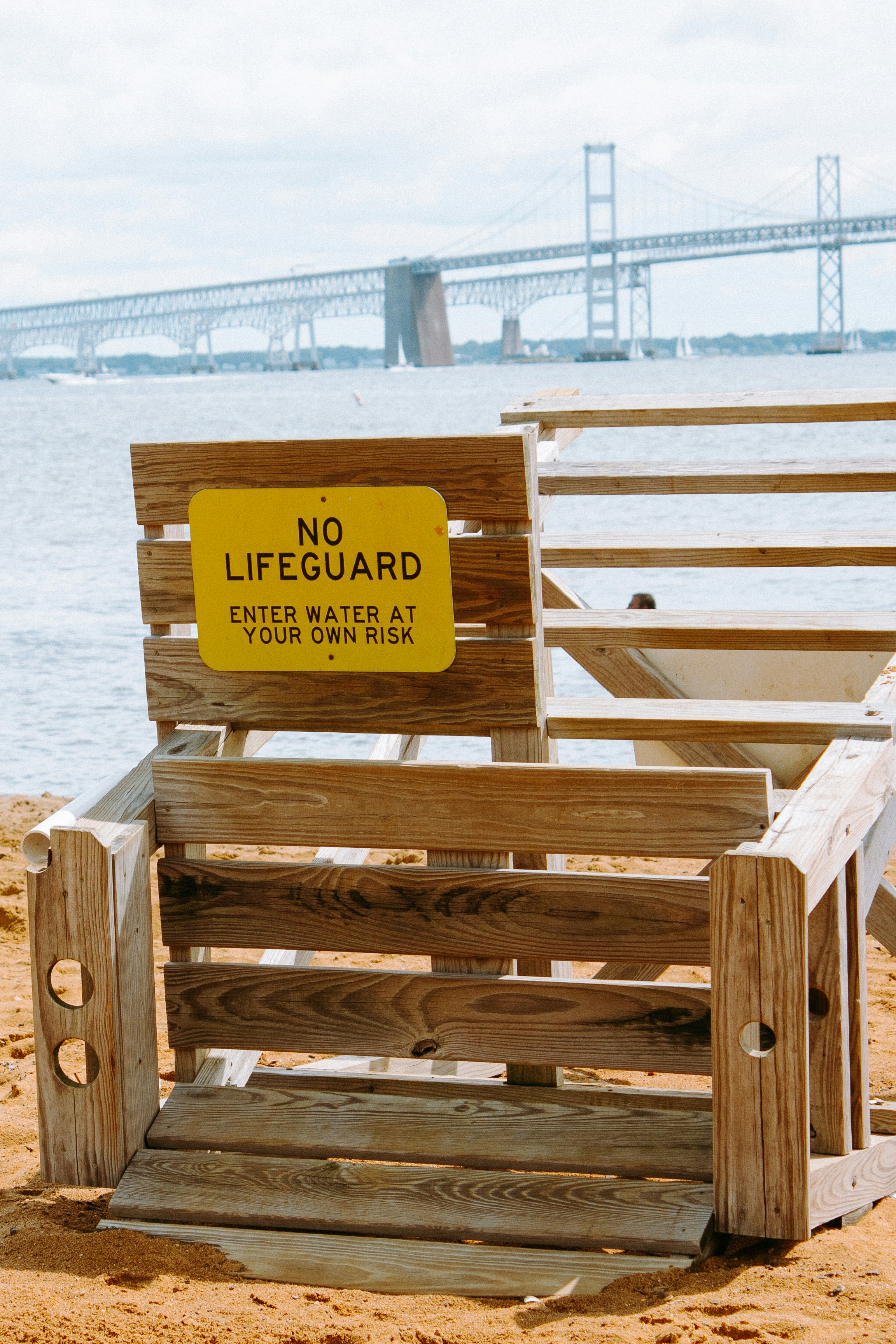 Weathered Lifeguard Chair by the Shore, Watching Over a Distant Bridge