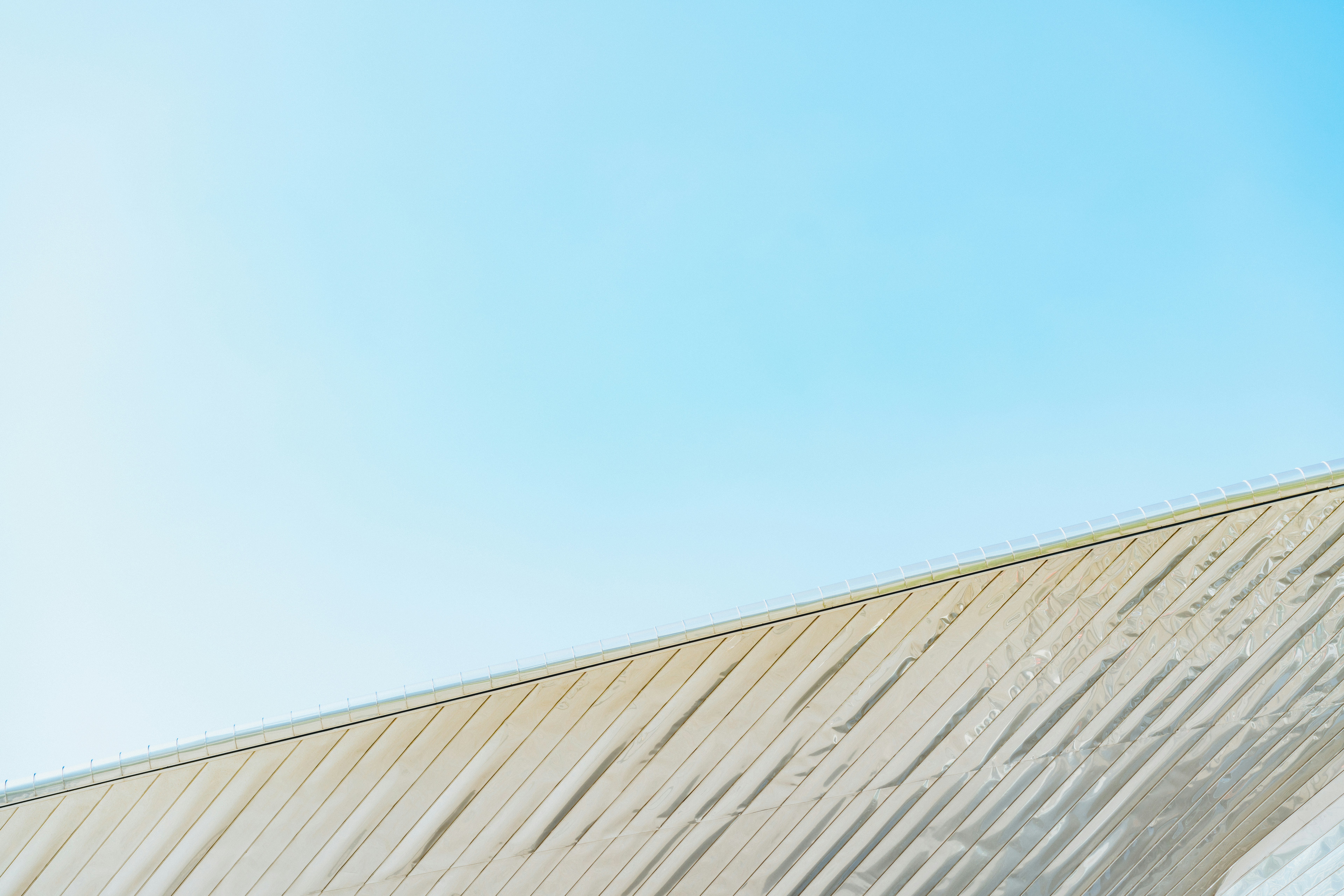 Sand dune etched with wind patterns beneath a clear blue sky.