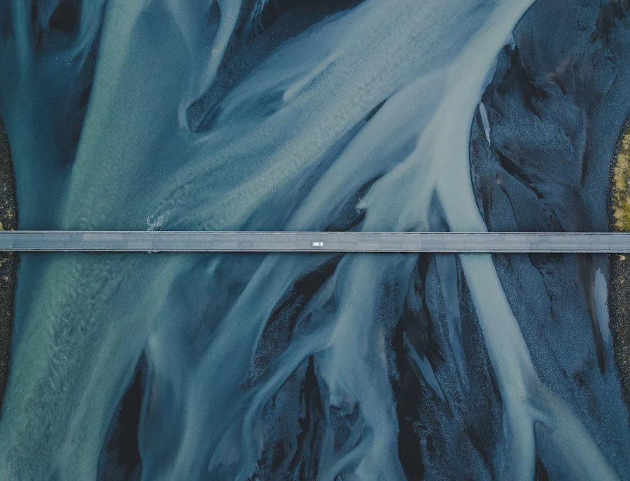 It’s often hard to see the beauty that’s right under your feet — or car. Flew a drone to capture this gorgeous river that almost looks like a painting. | an aerial view of a road in the middle of a river