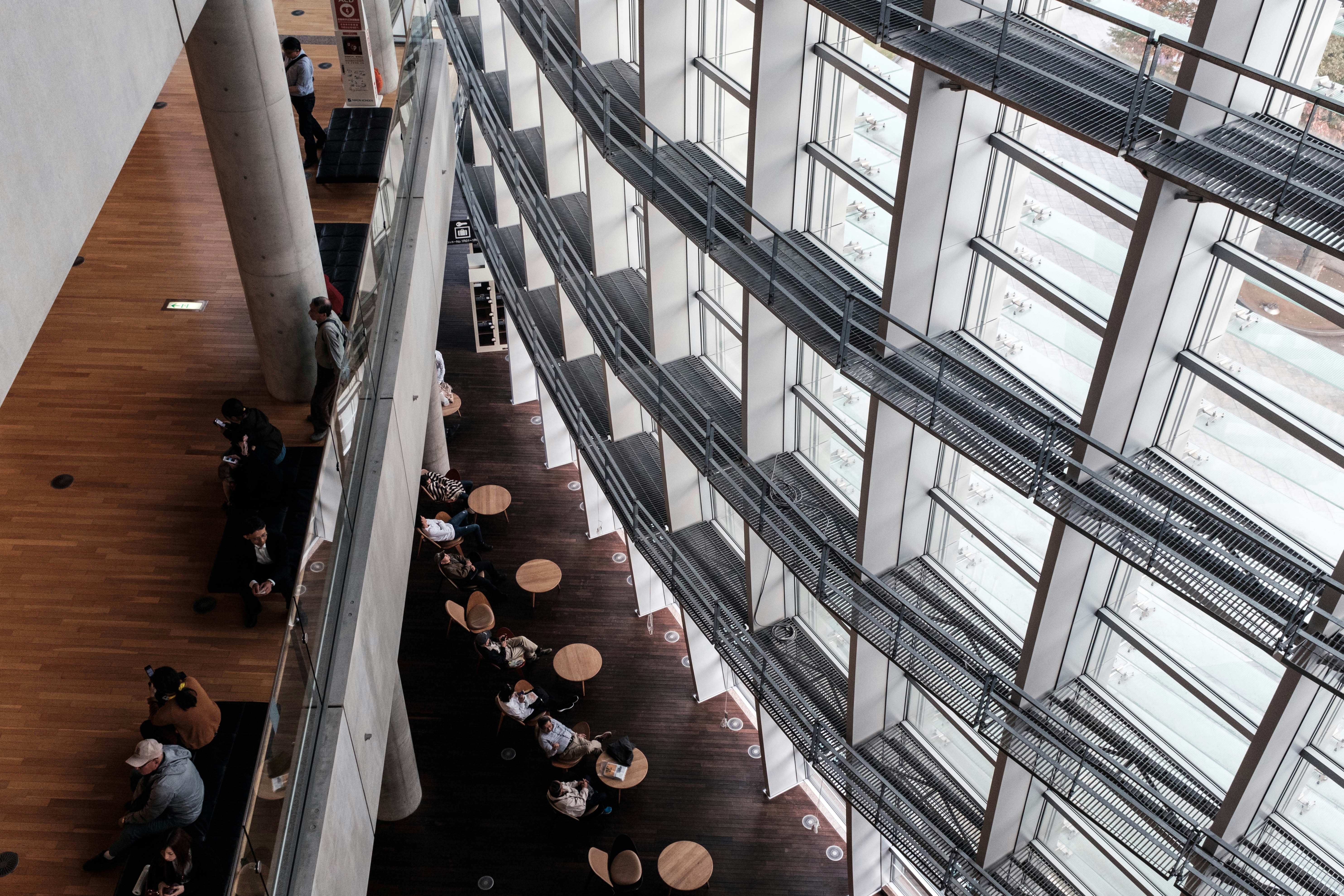 Interior view from above showcasing a modern, airy atrium with curved glass walls and scattered seating.