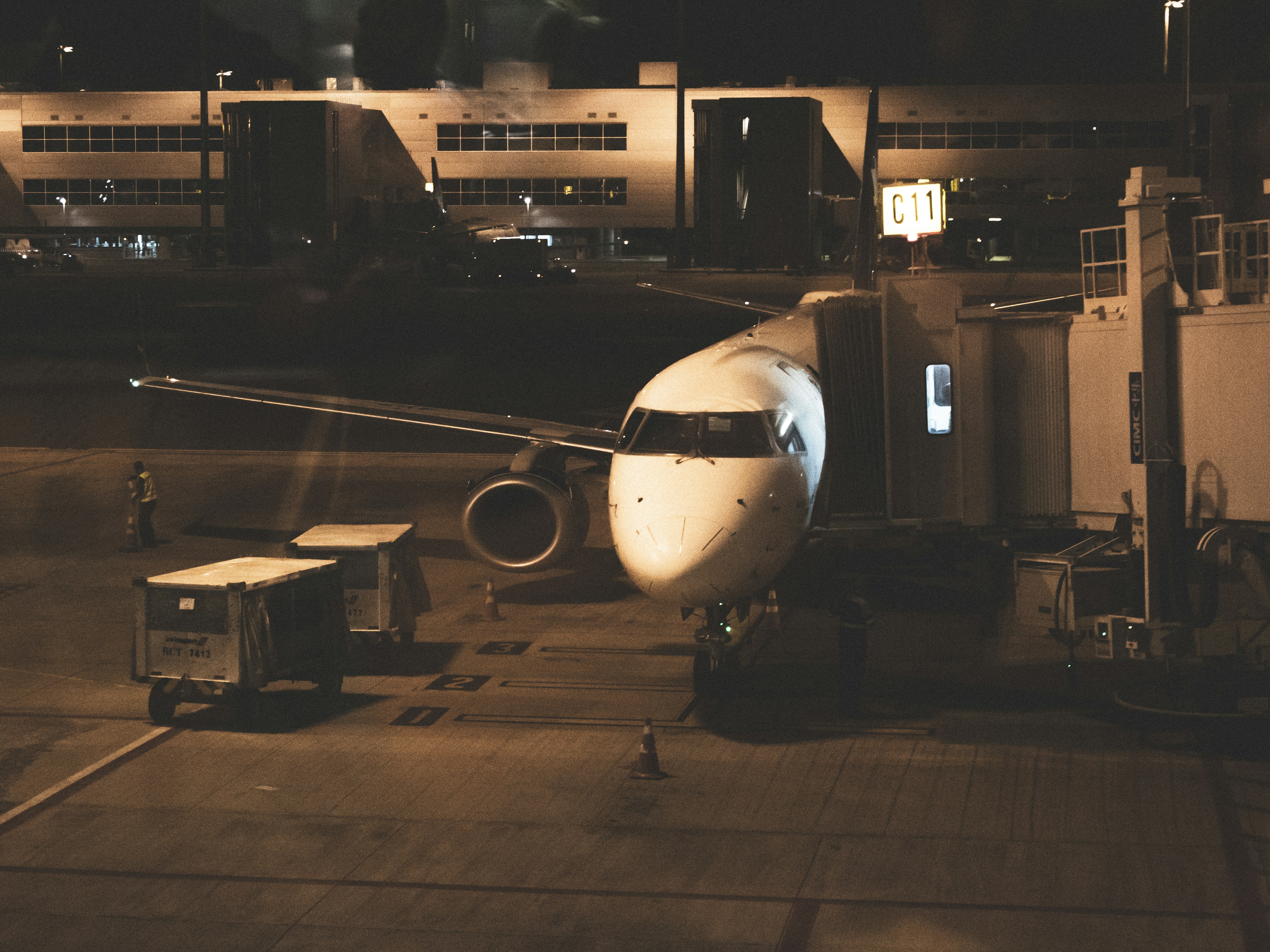 Airplane parked at the gate under dim airport lights, ready for boarding. The scene captures the essence of travel anticipation.