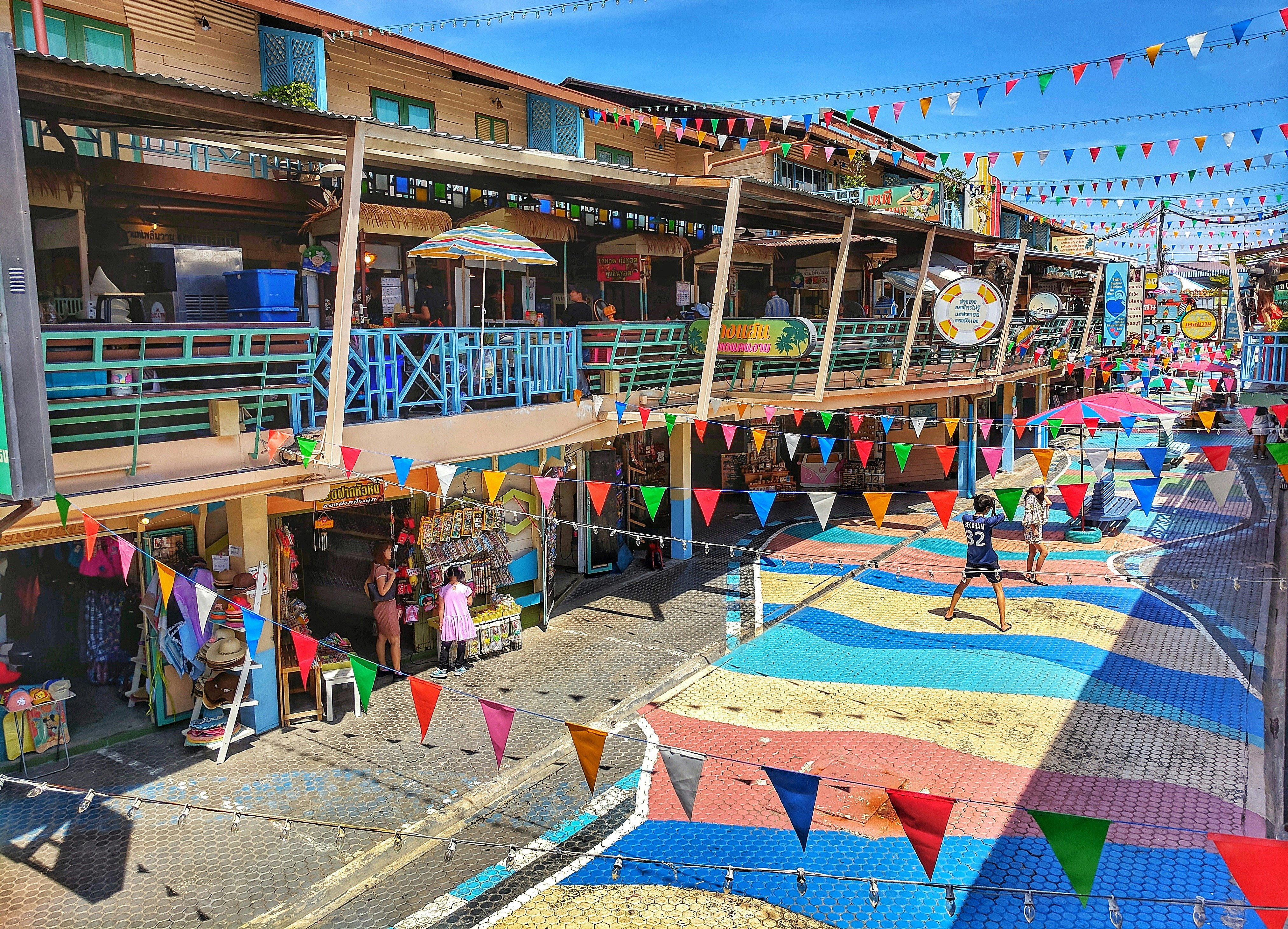 Colorful street with vivid murals and festive pennants under a clear blue sky.