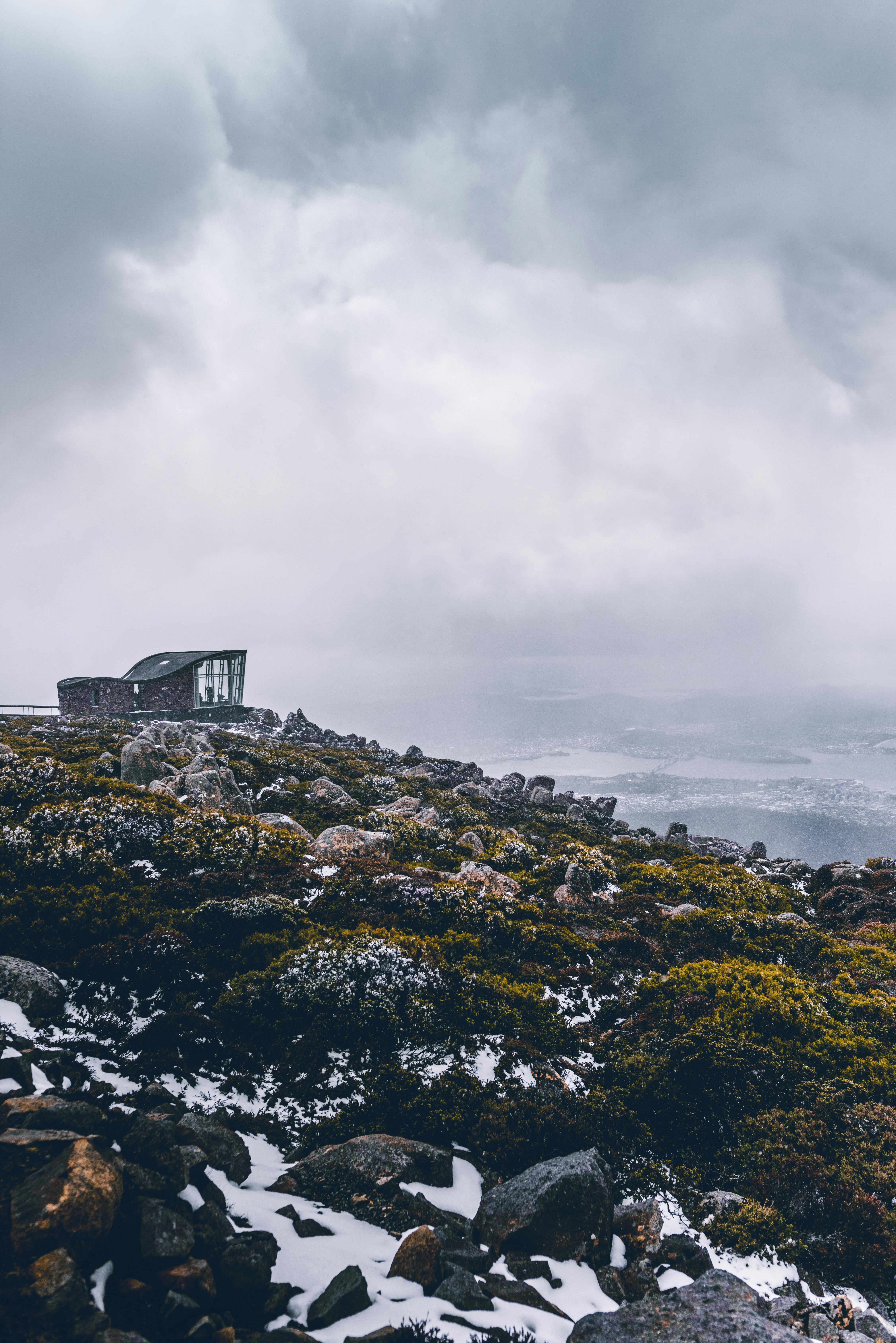 Stone Shelter on a Snow-Dusted Ridge Beneath a Churning Sky