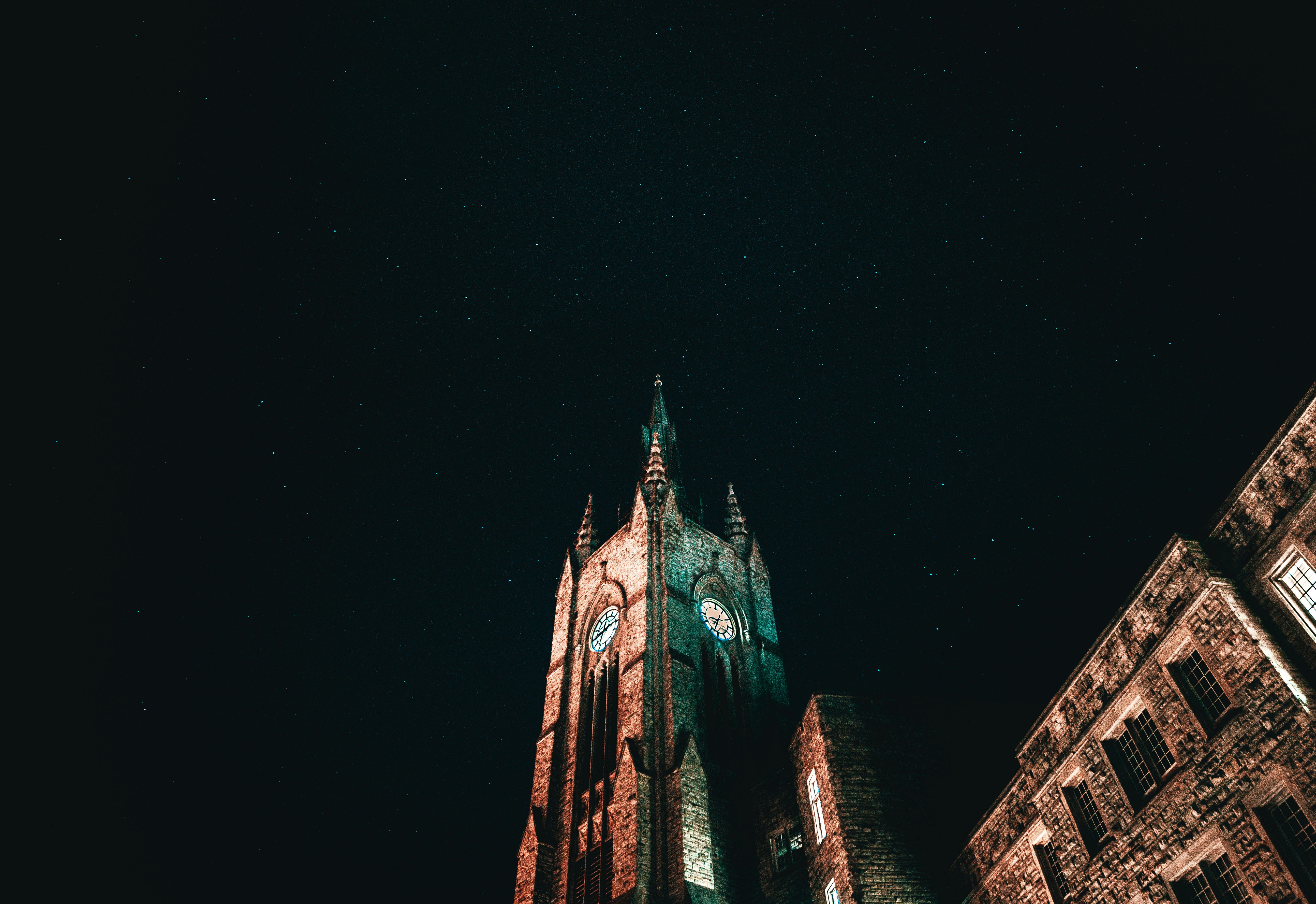 Gothic church tower illuminated against a starry night sky, showcasing intricate architectural details and a sense of grandeur.