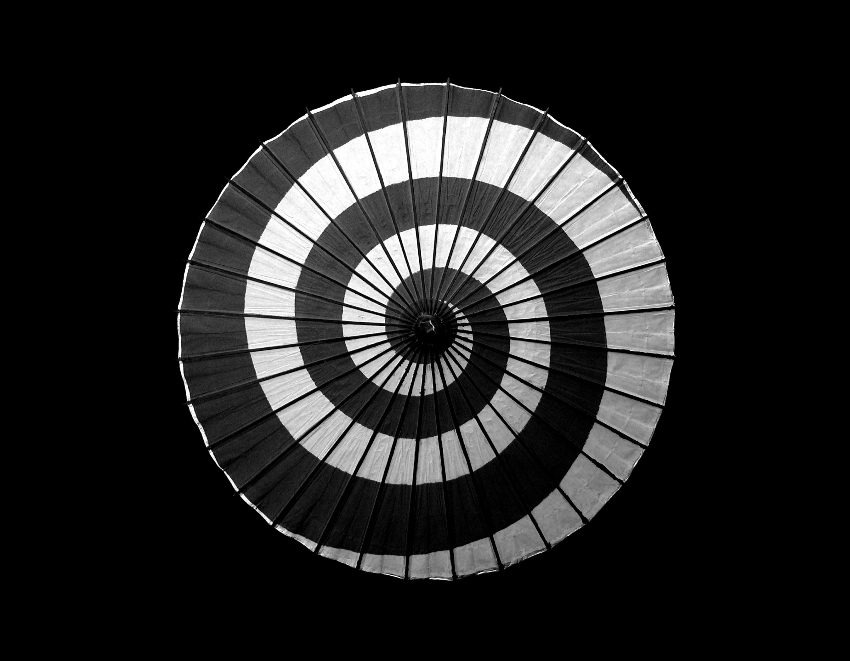 Black and white Japanese umbrella with concentric circles against a dark background.
