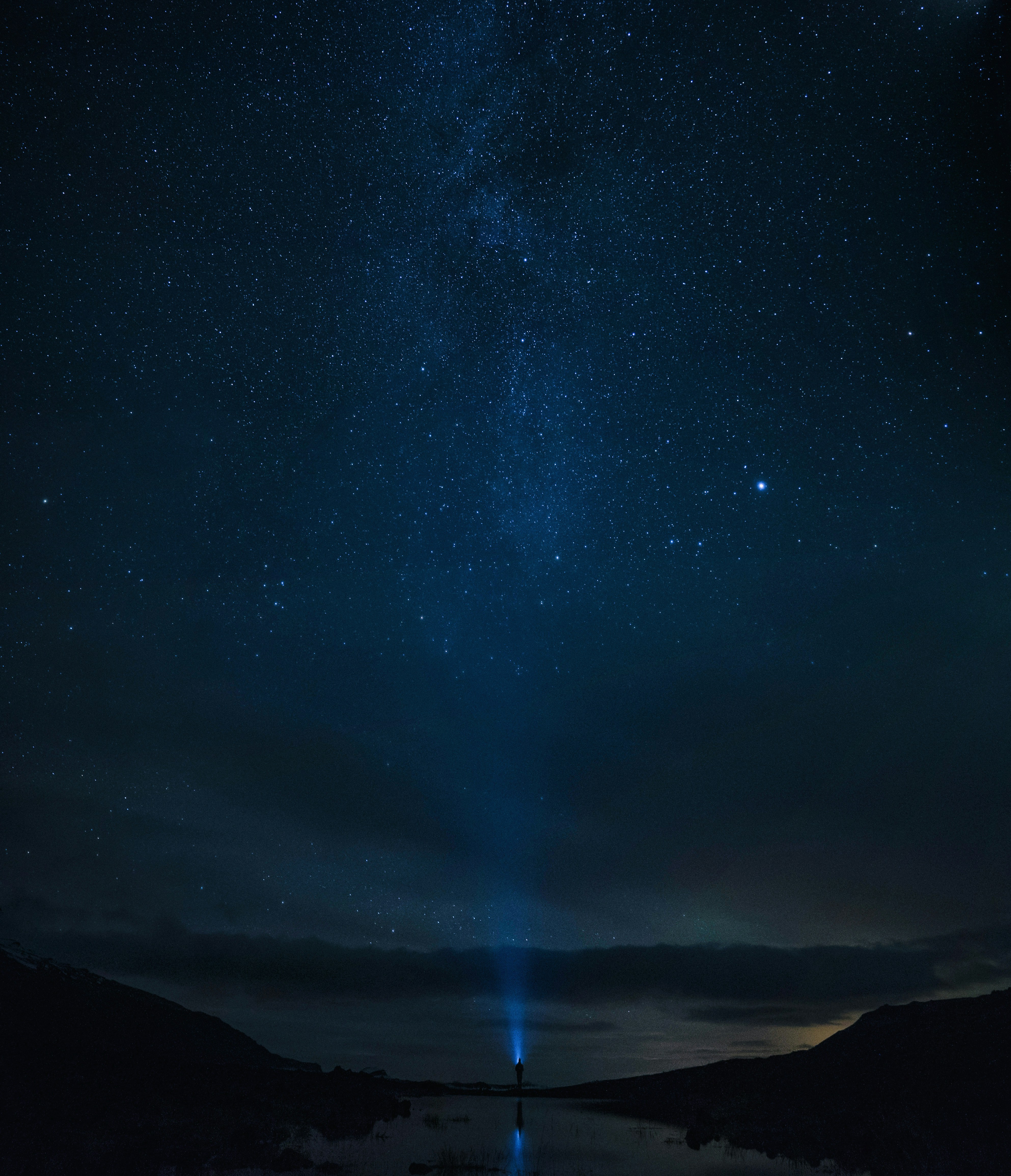 Person light flashlight up towards the sky during star filled sky photo ...
