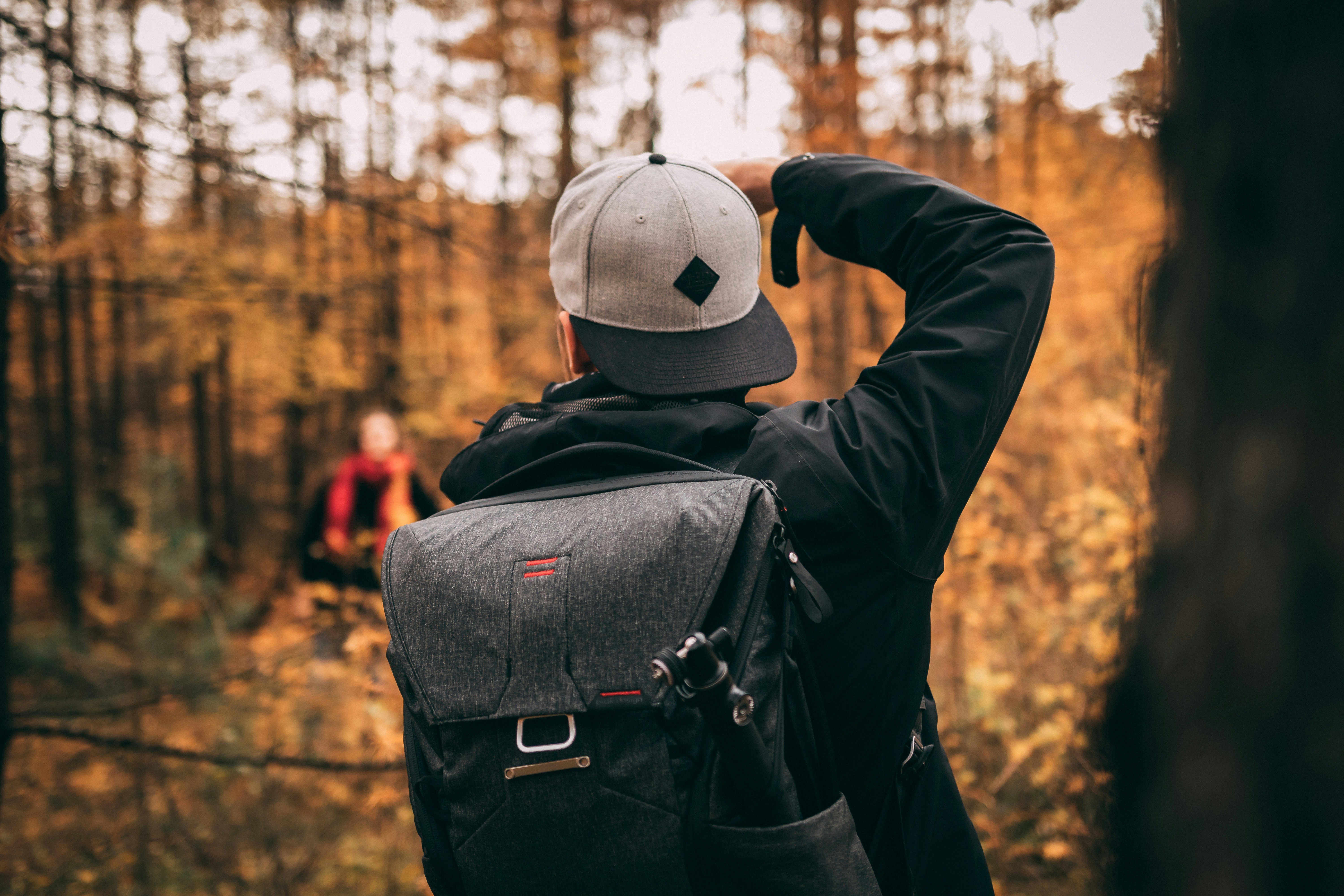 Person photographing autumn foliage in a wooded area during daytime.