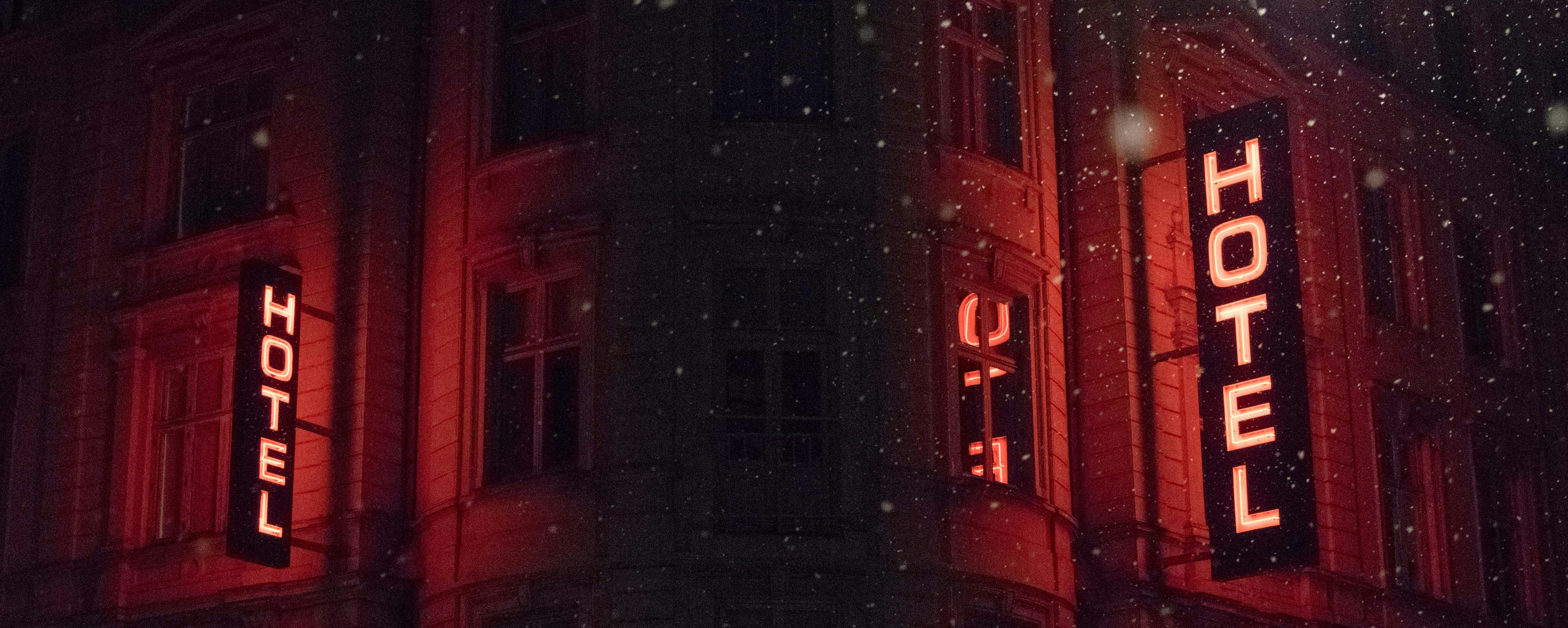 Illuminated hotel signs glow in vibrant red against a snowy backdrop, creating a warm contrast to the winter scene.
