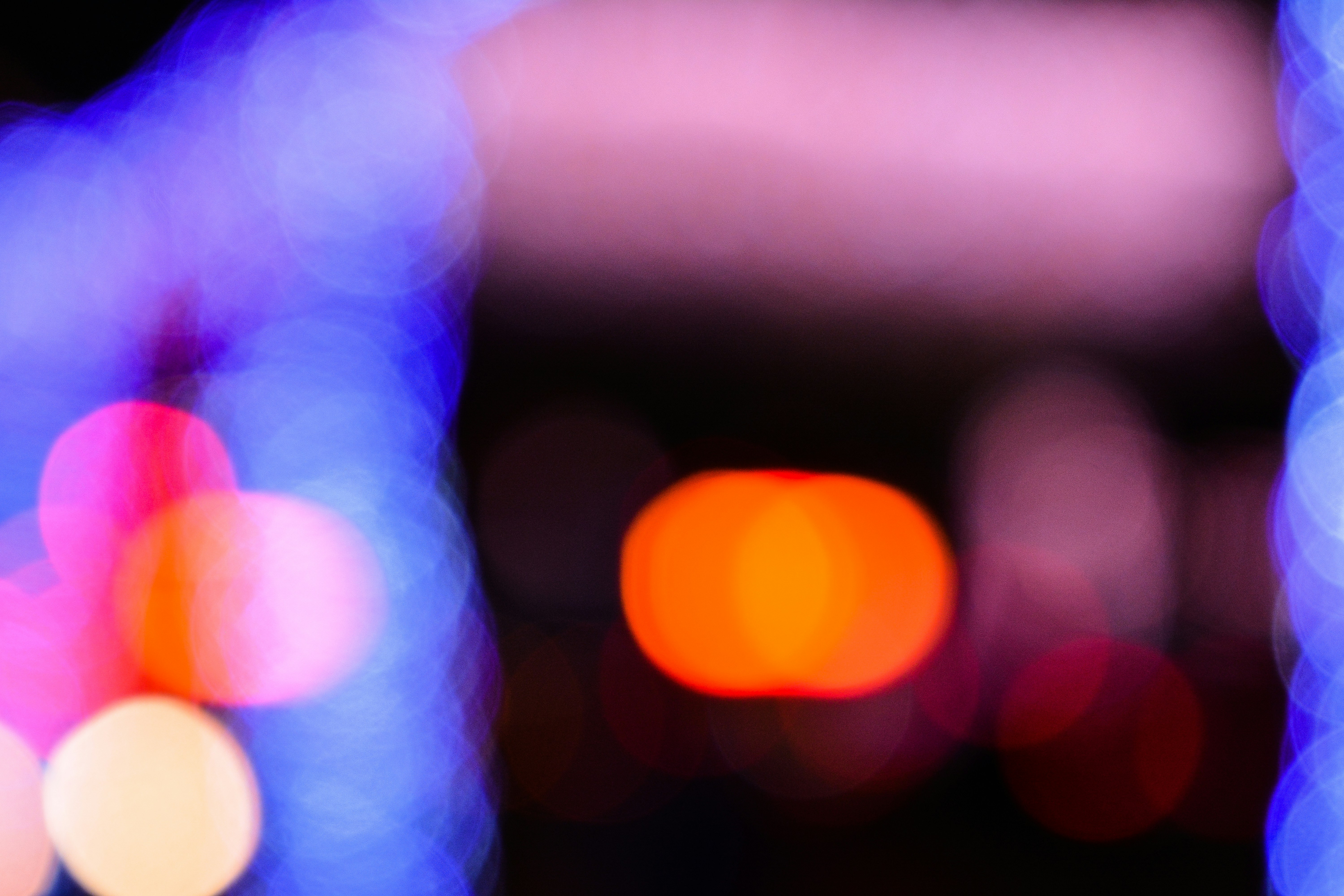 Abstract bokeh of vibrant blue, pink, and orange lights in a blurred urban setting.