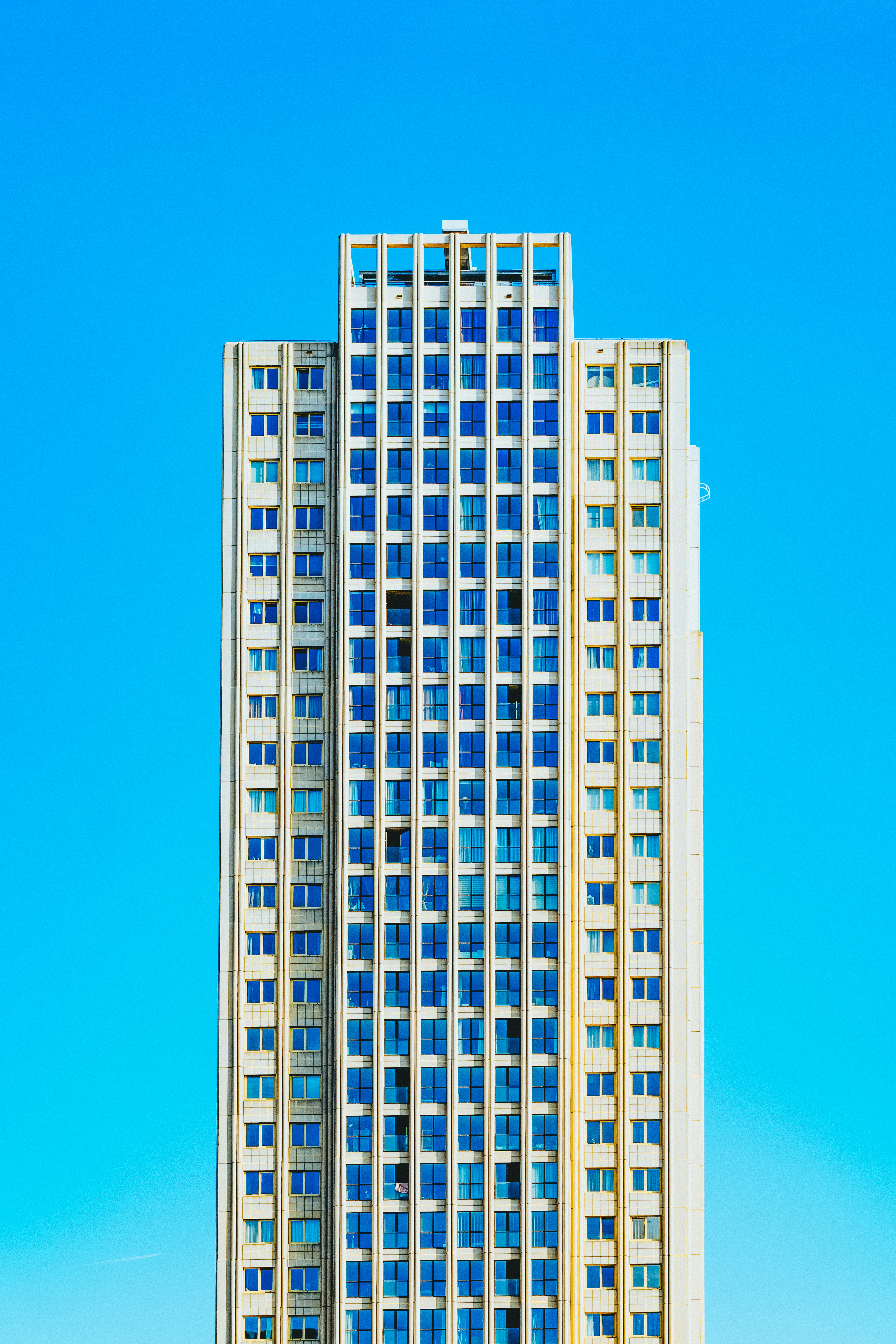 Tall building with grid-like window pattern set against a bright blue sky.