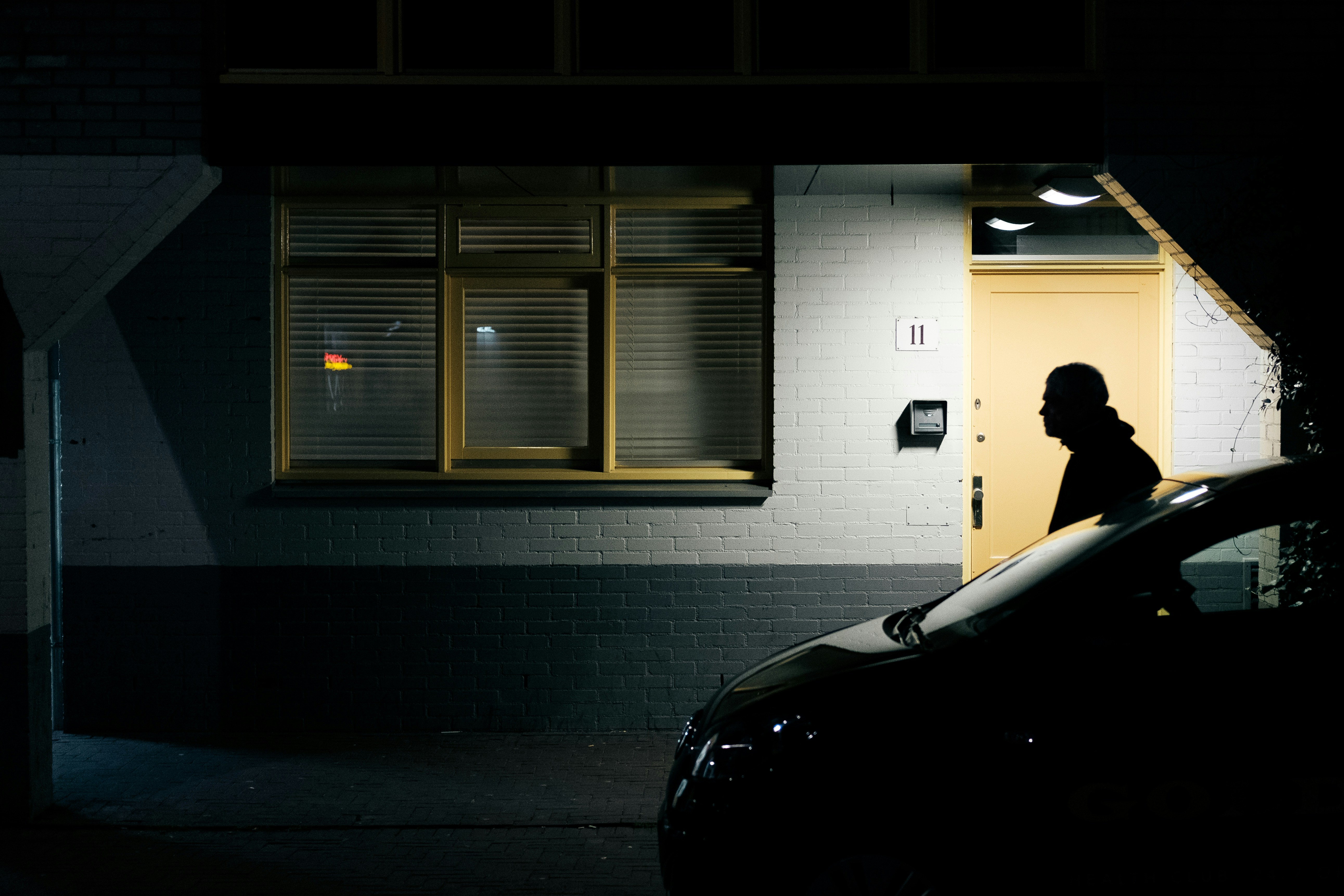 Silent Passage by Warm Light: A Lone Figure at a Yellow Door