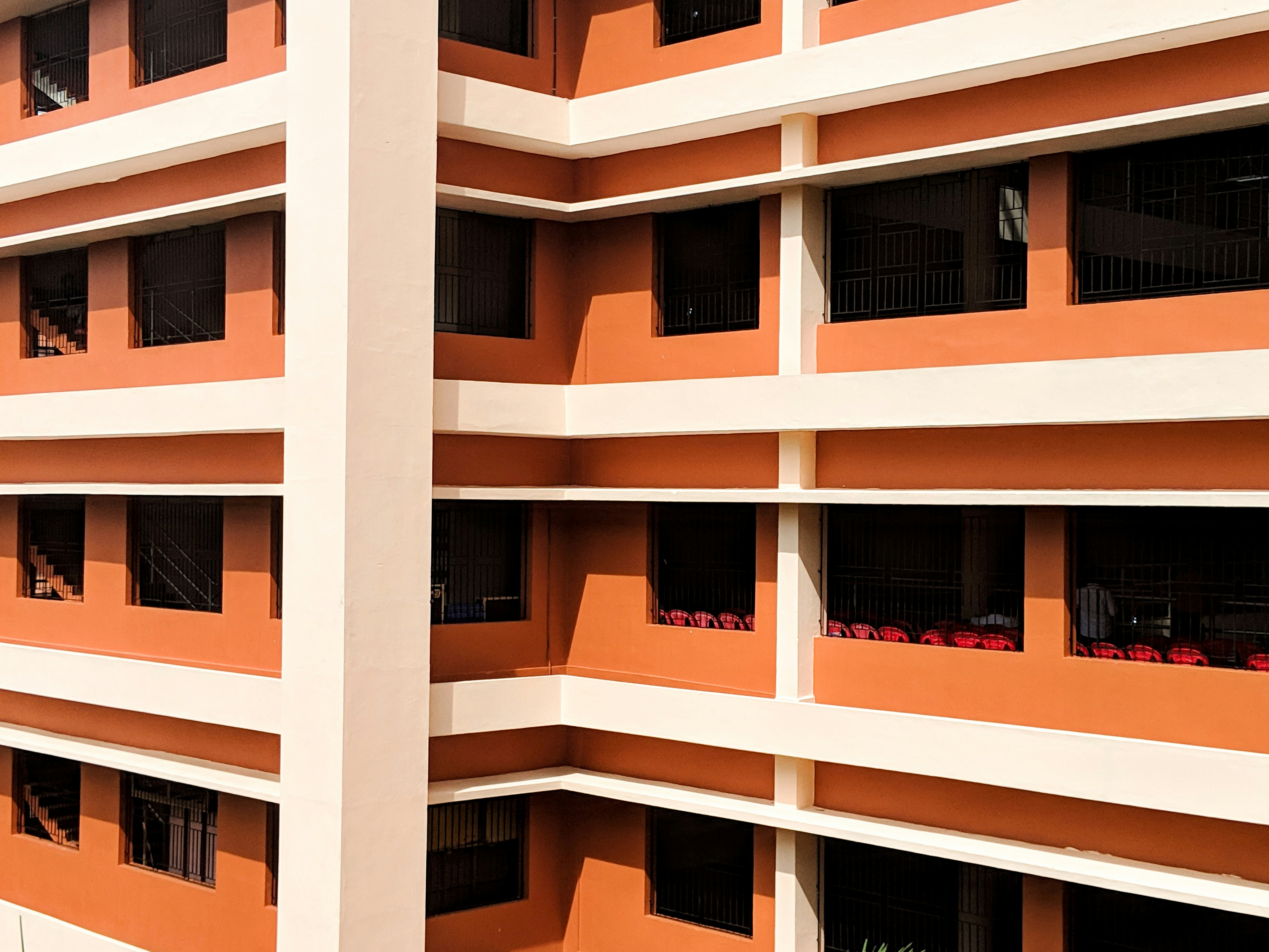 Facade of a building with orange and cream geometric patterns and dark windows.