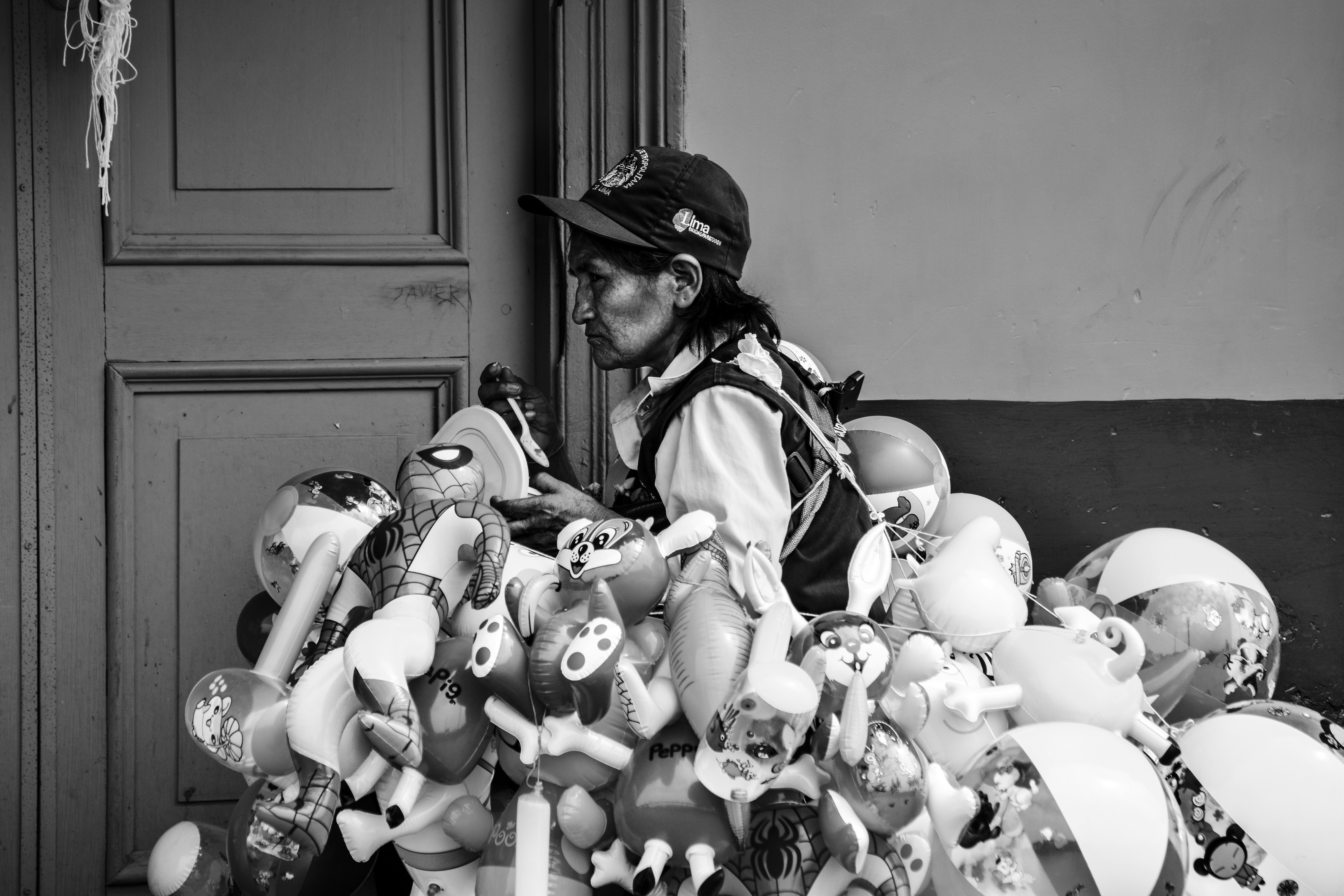 Balloons spilling from a doorway: a solitary vendor in grayscale