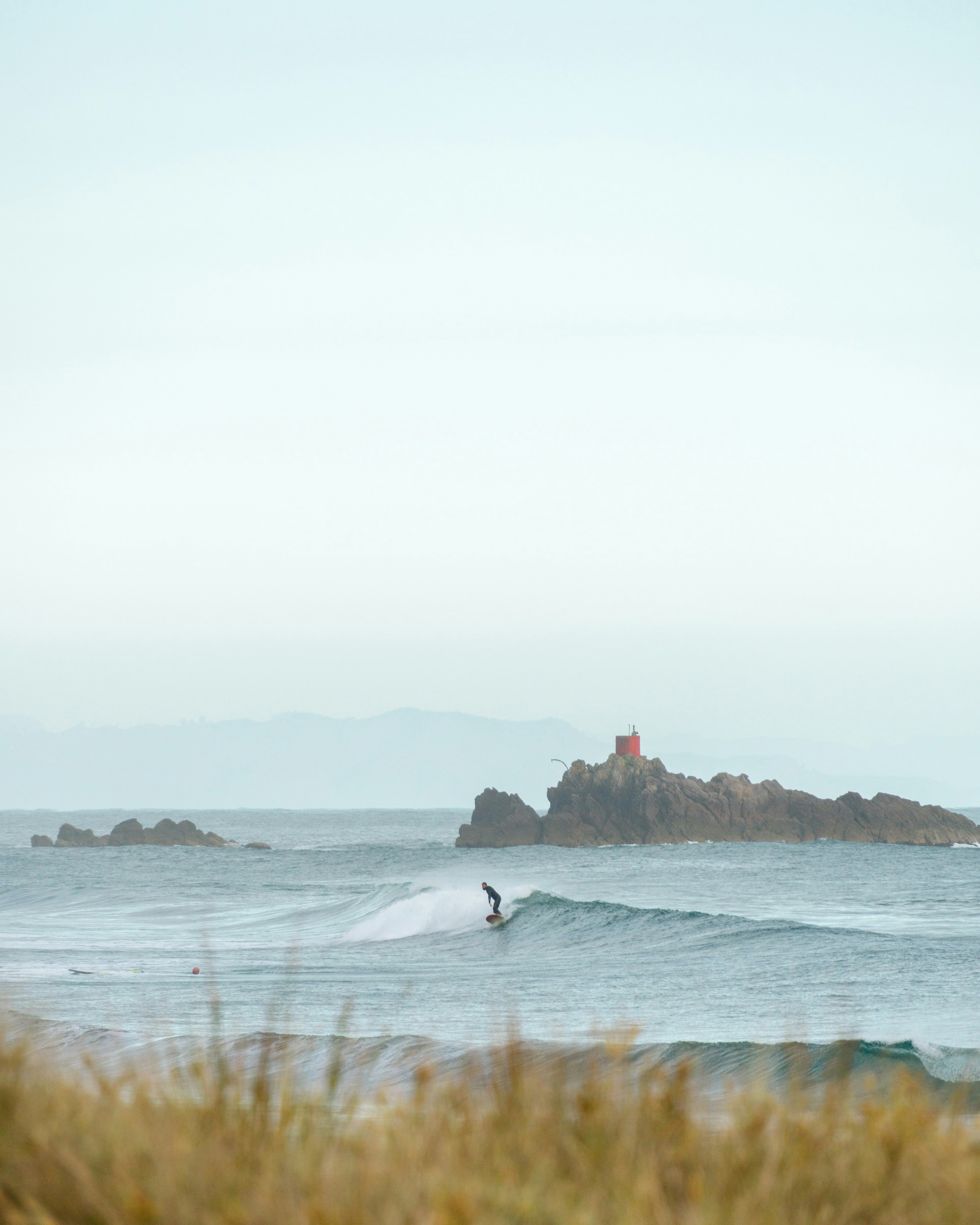 Surf Rider Above Quiet Blue: Wave Rider near a Red‑Top Lighthouse